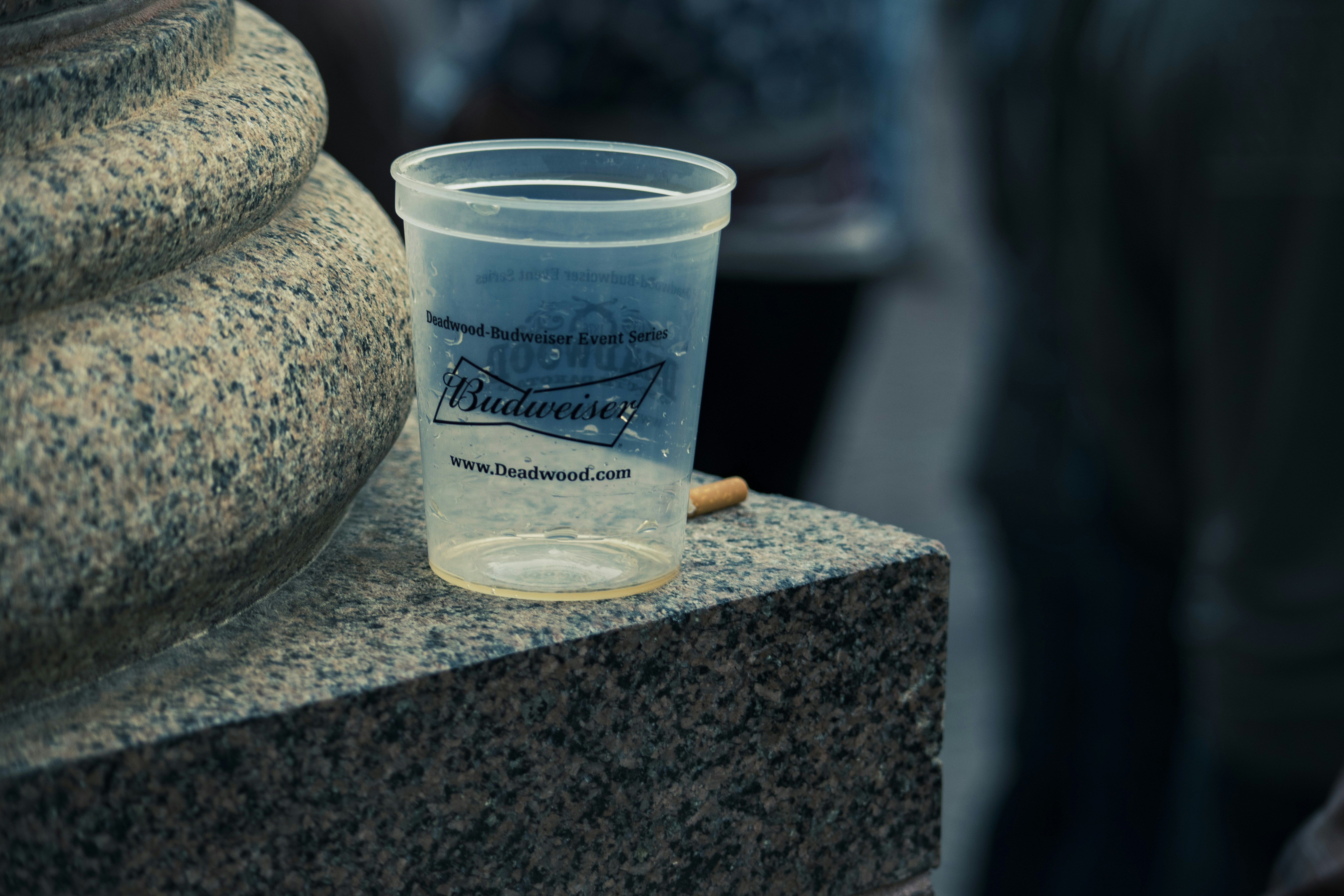 A Budweiser cup perched on a granite ledge beside a shadowy backdrop