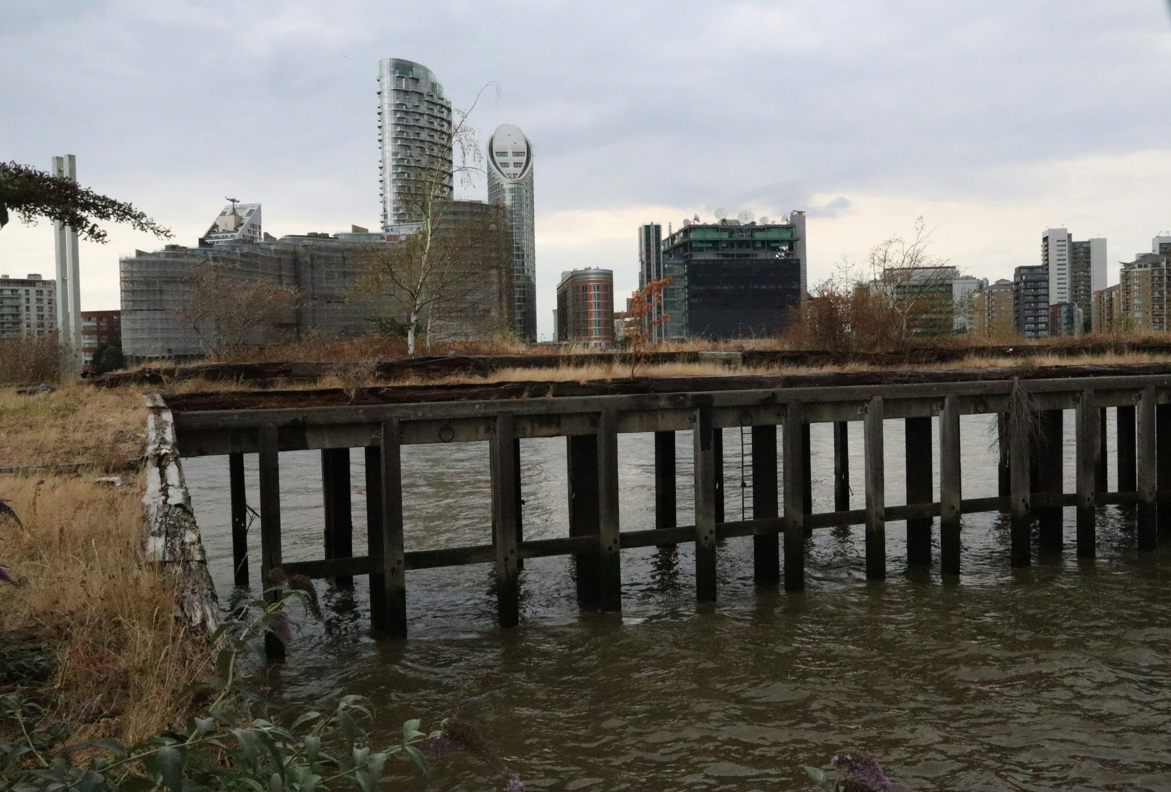 Weathered Pier Framing a Modern Riverside Skyline