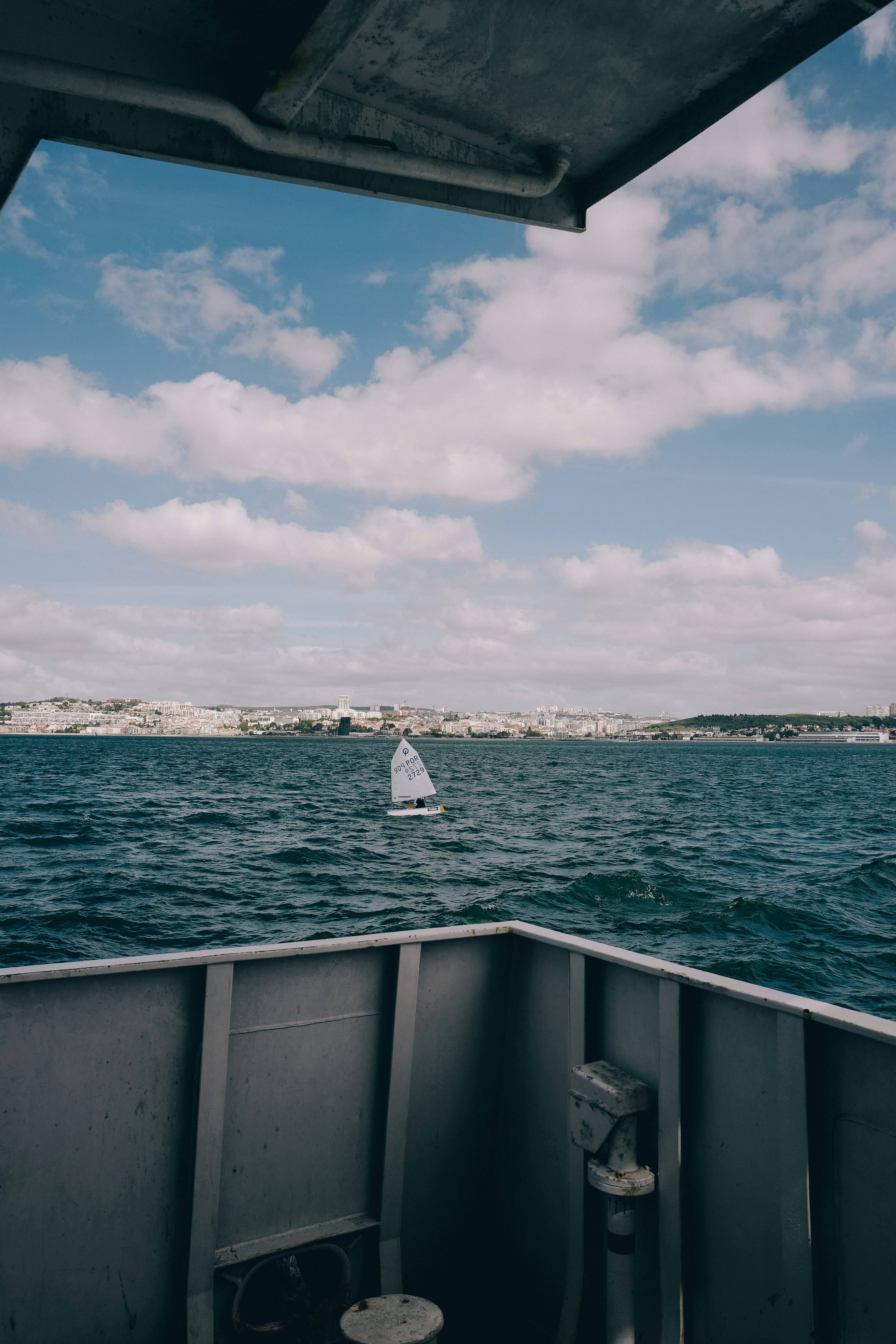 Distant Sail Against a City Skyline