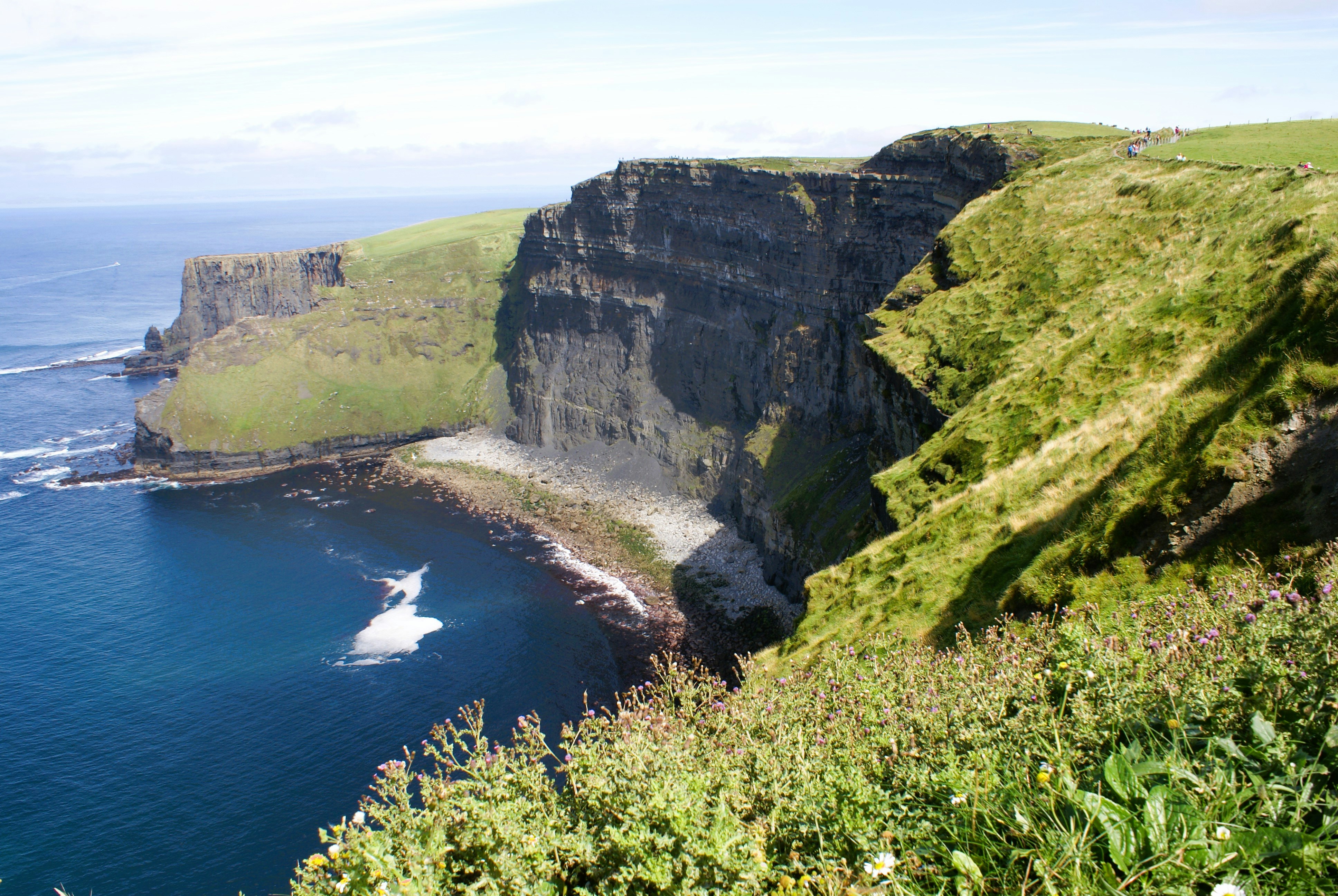 A cliff with a body of water below with Cliffs of Moher in the ...