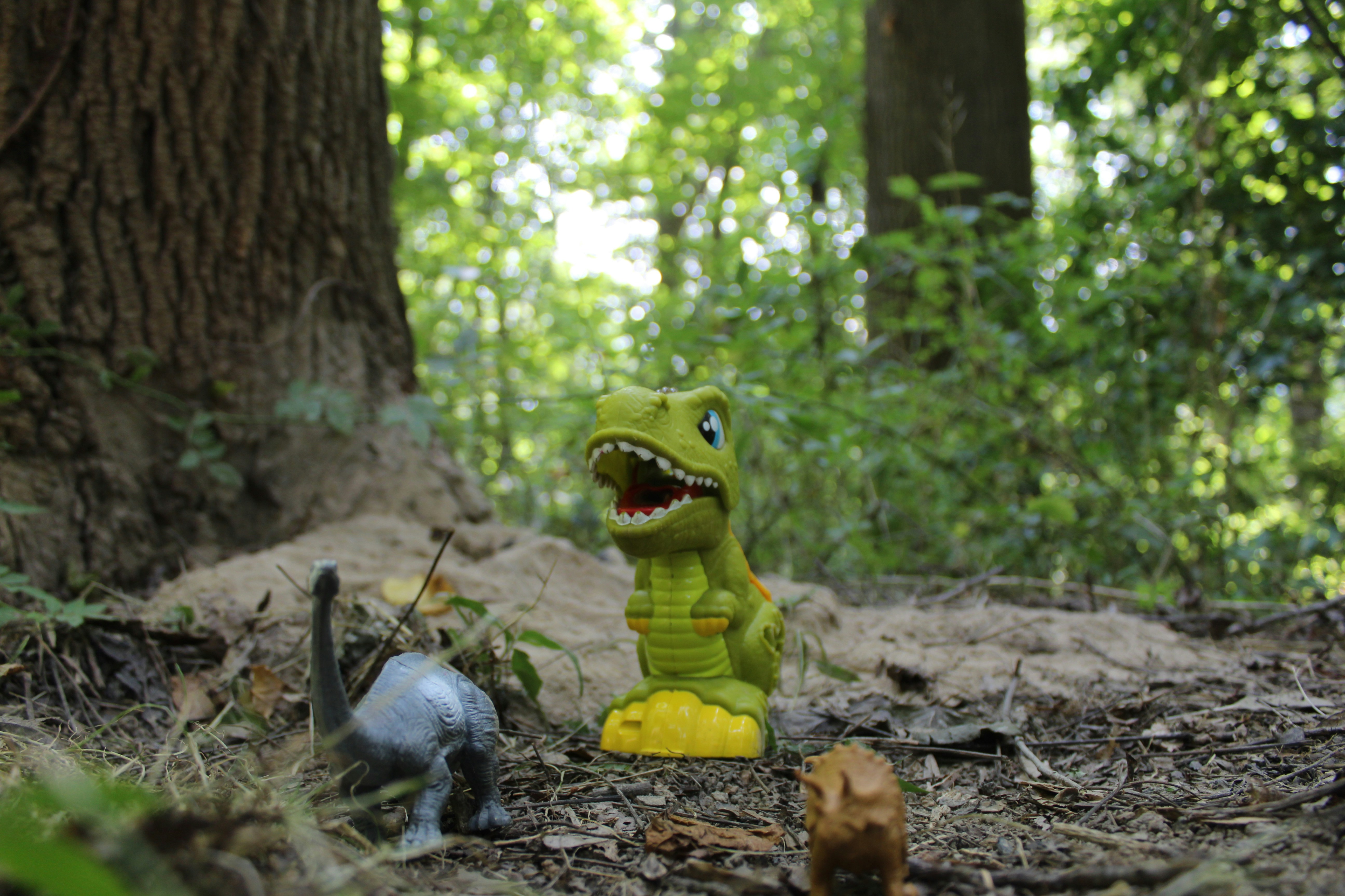 Tiny Green Dinosaur Stands Guard on a Sunlit Forest Floor