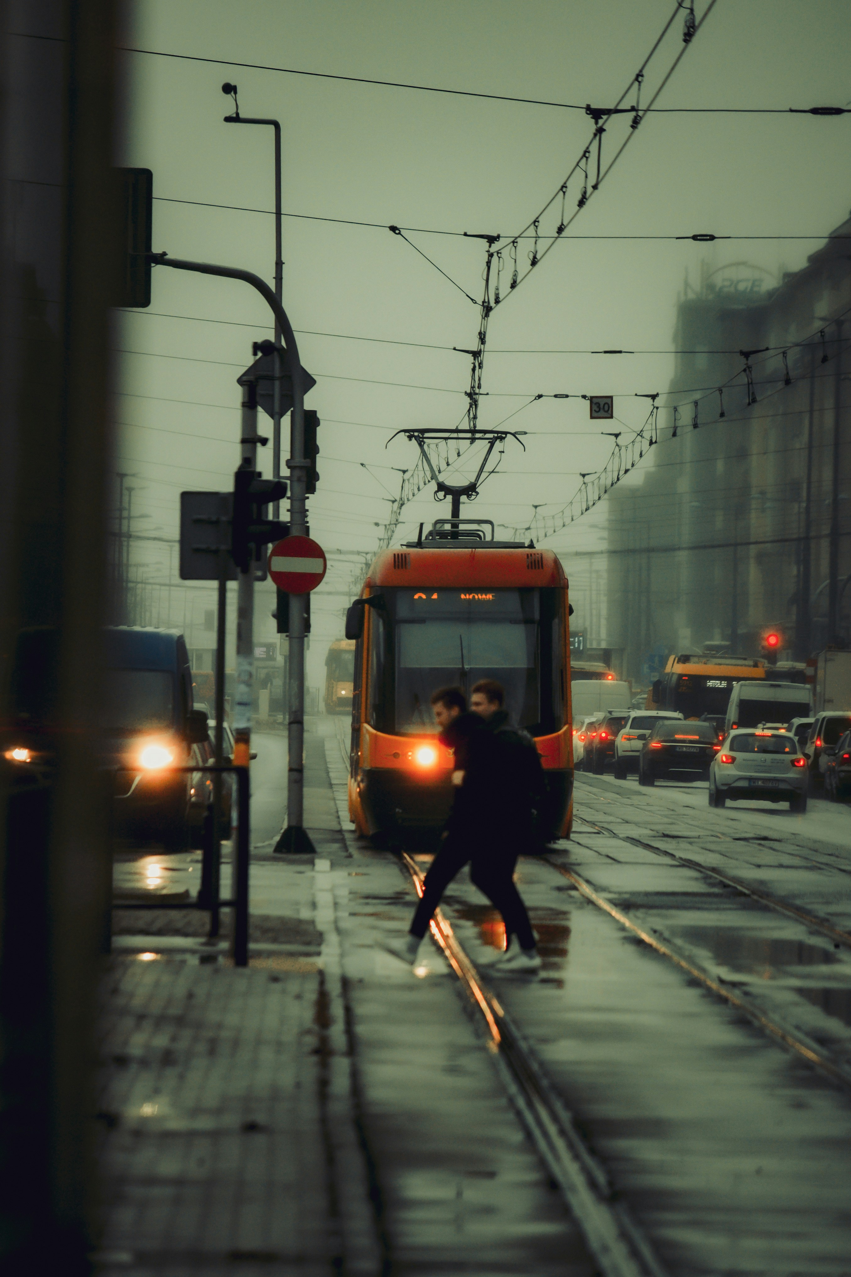 Orange Tram on Rain-Soaked Rails: A City Moment of Crossing Motion