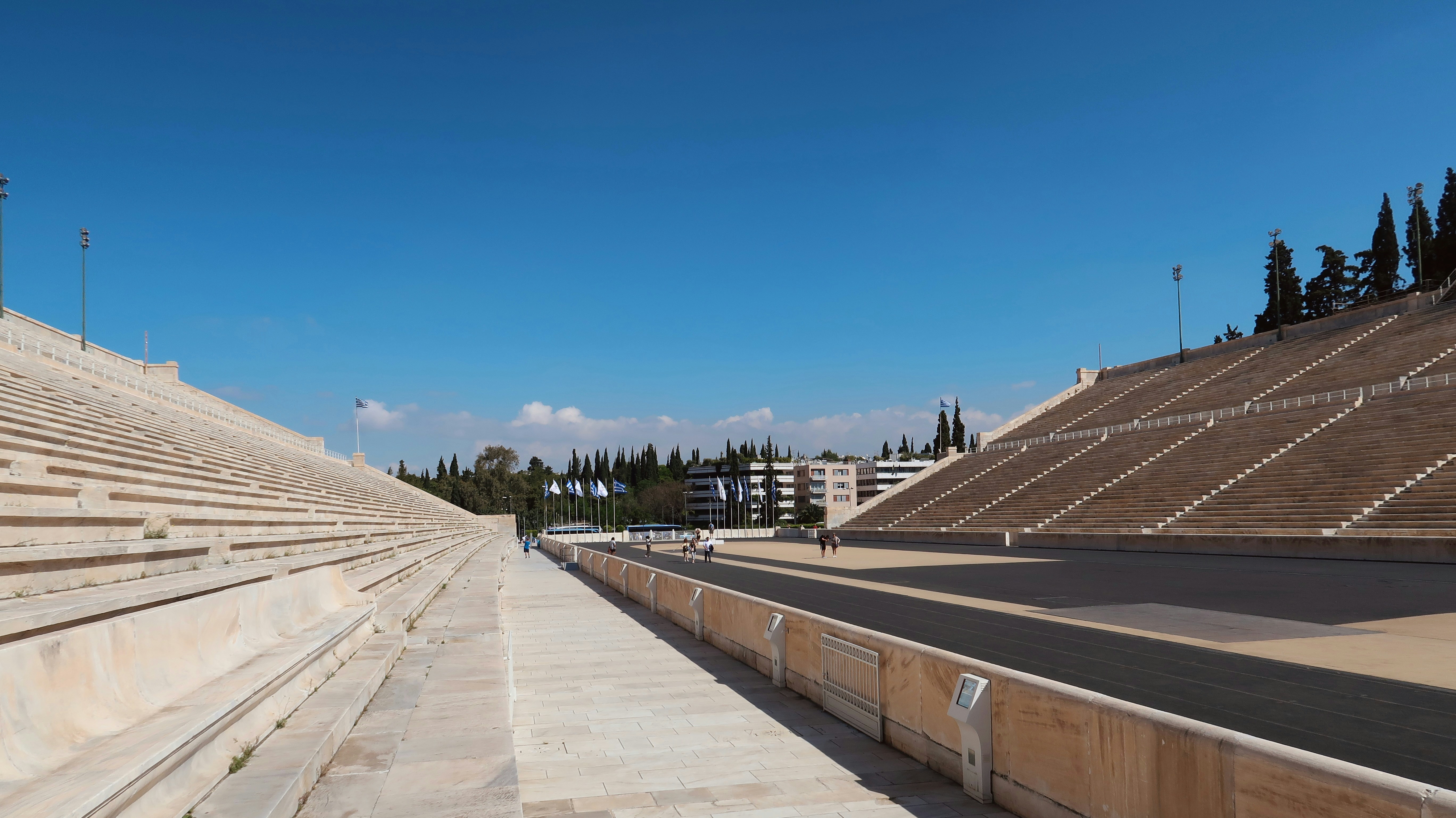 A road with a wall and a fence on the side with Panathenaic Stadium in ...