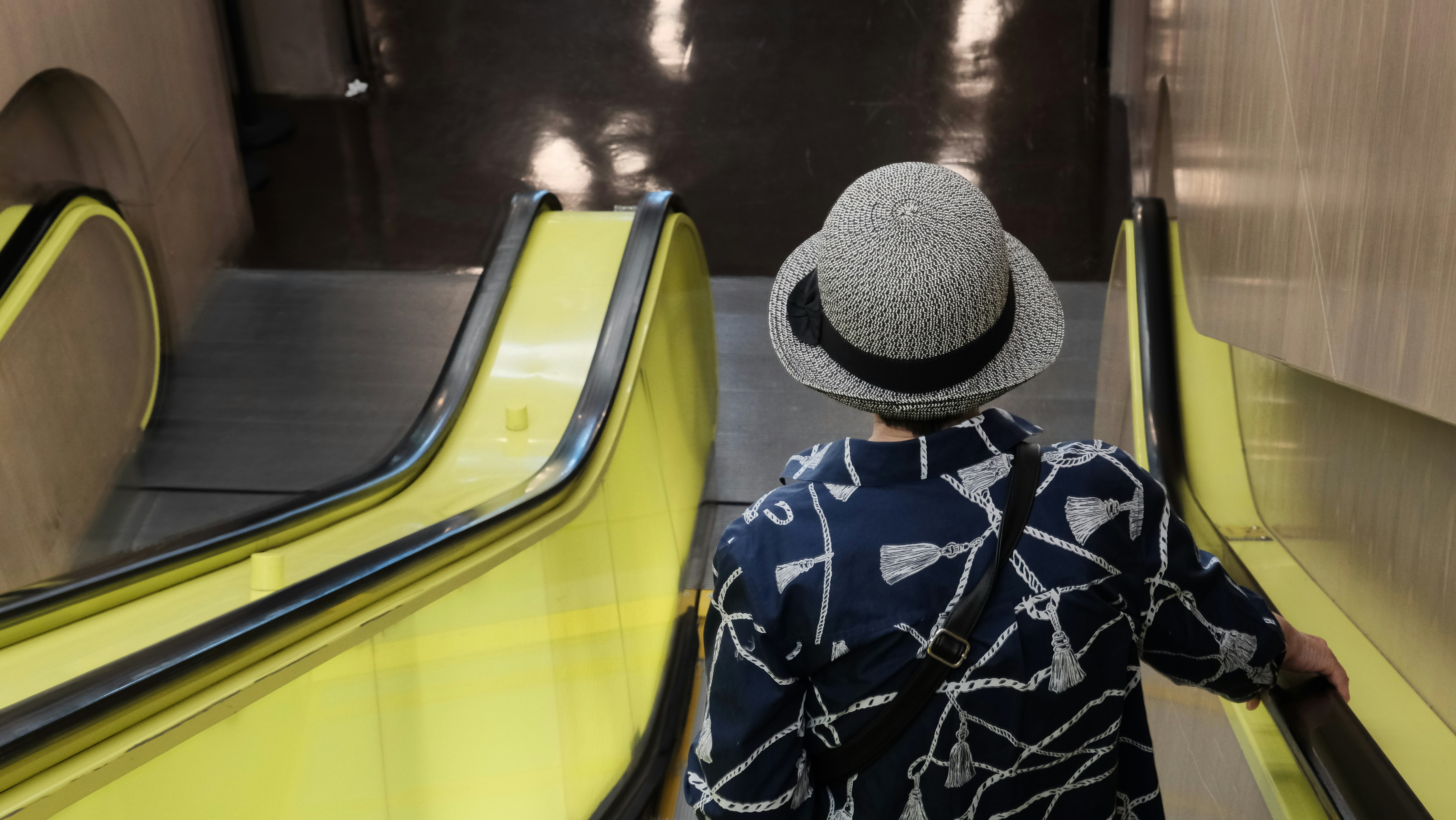 Traveler in a Neonlit Mall Corridor Ascends a Quiet Escalator