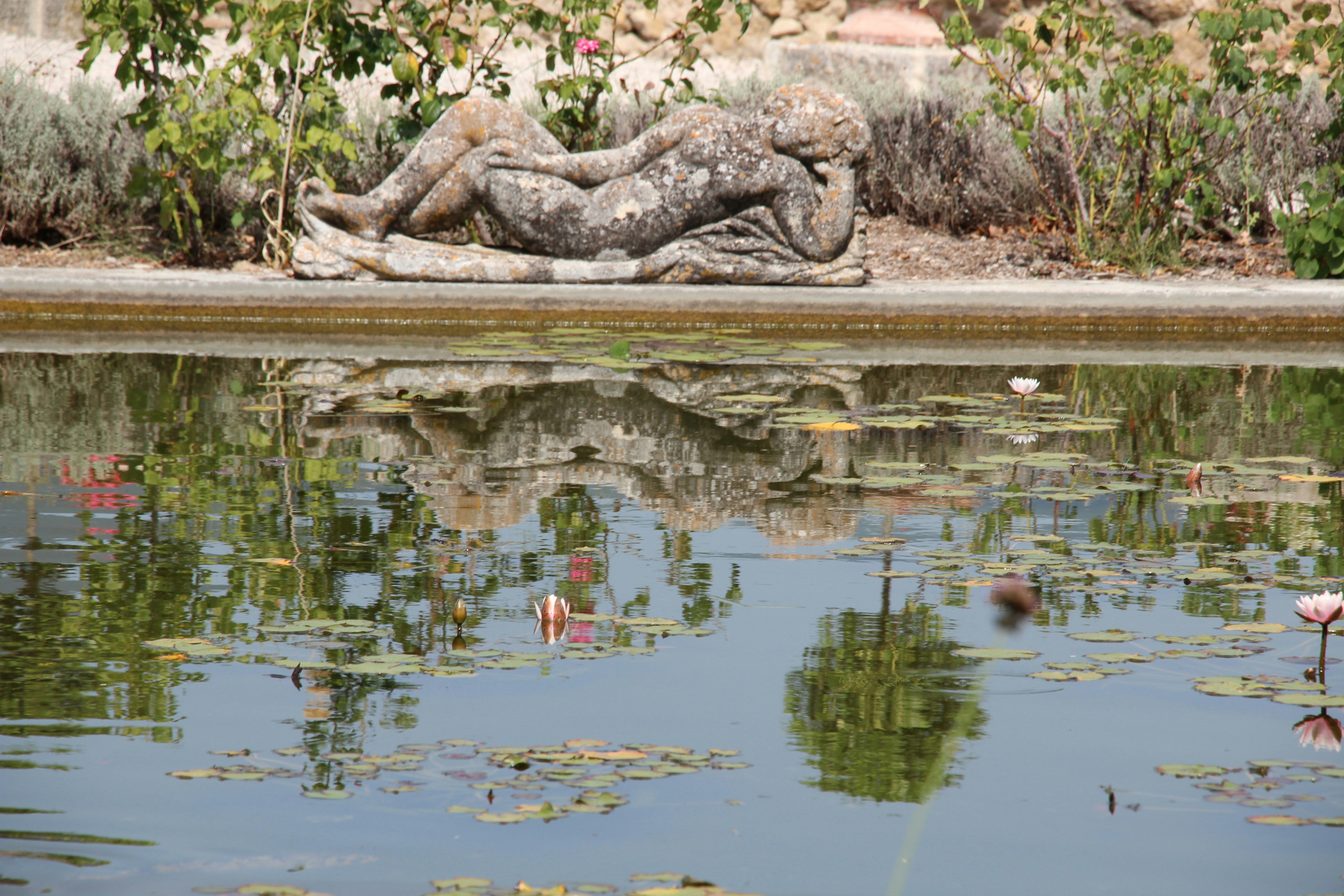 Stone Lovers by the Pond: a garden sculpture mirrored in tranquil water