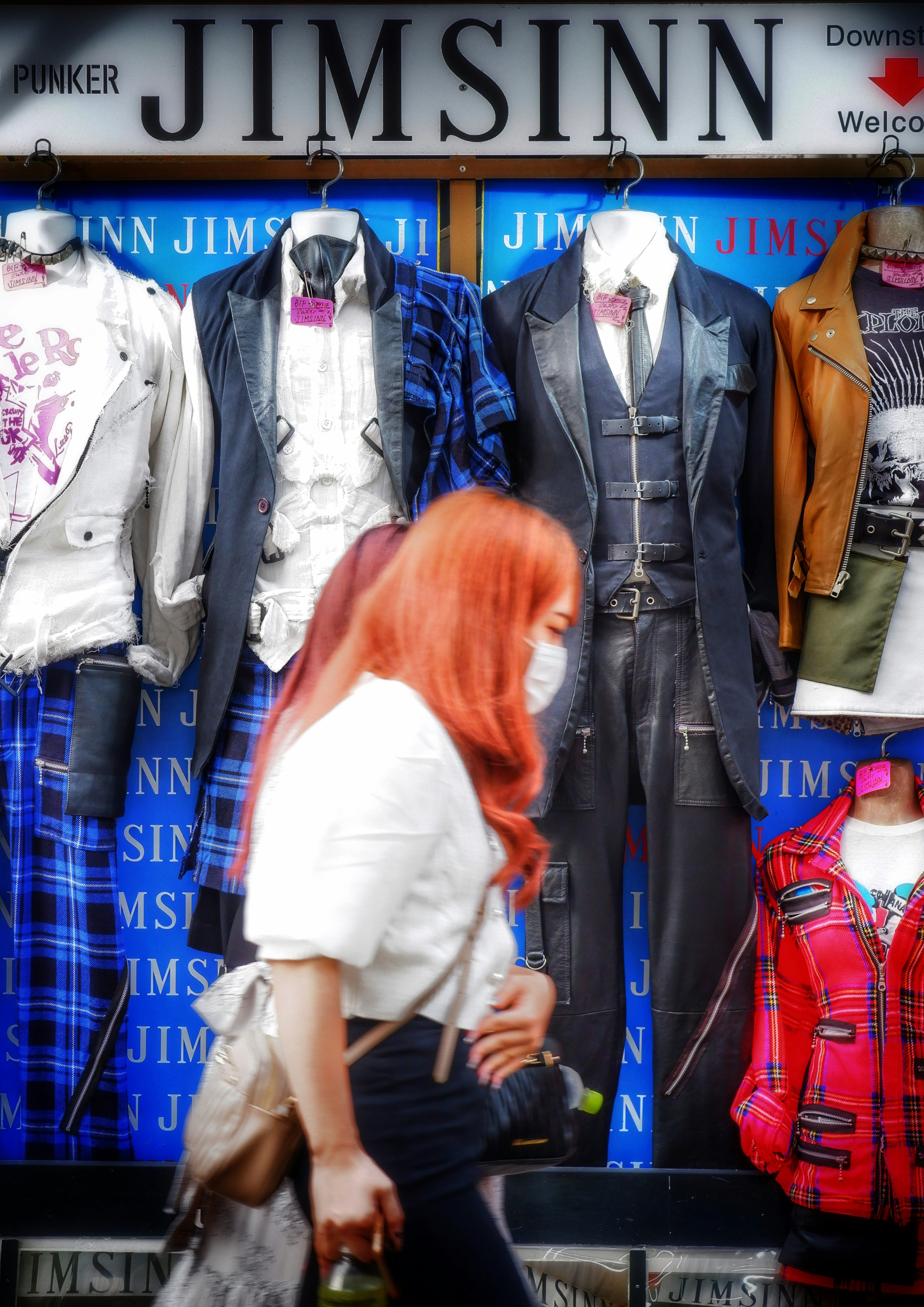 Vibrant storefront display with mannequins and a blurred passerby