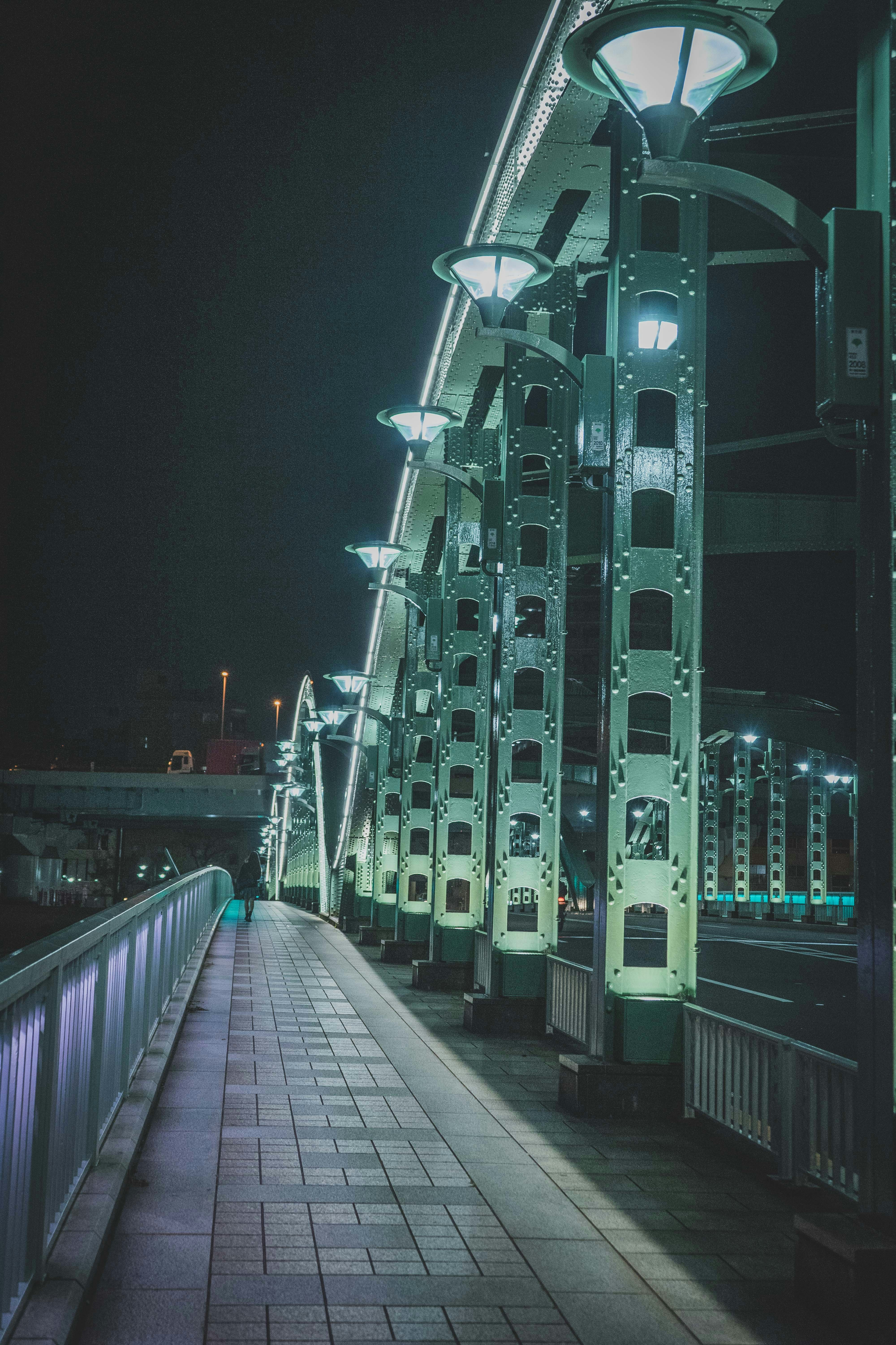 Teal Lanterns on a Night-Worn Bridge: Receding Steel Arches and Quiet Walkway