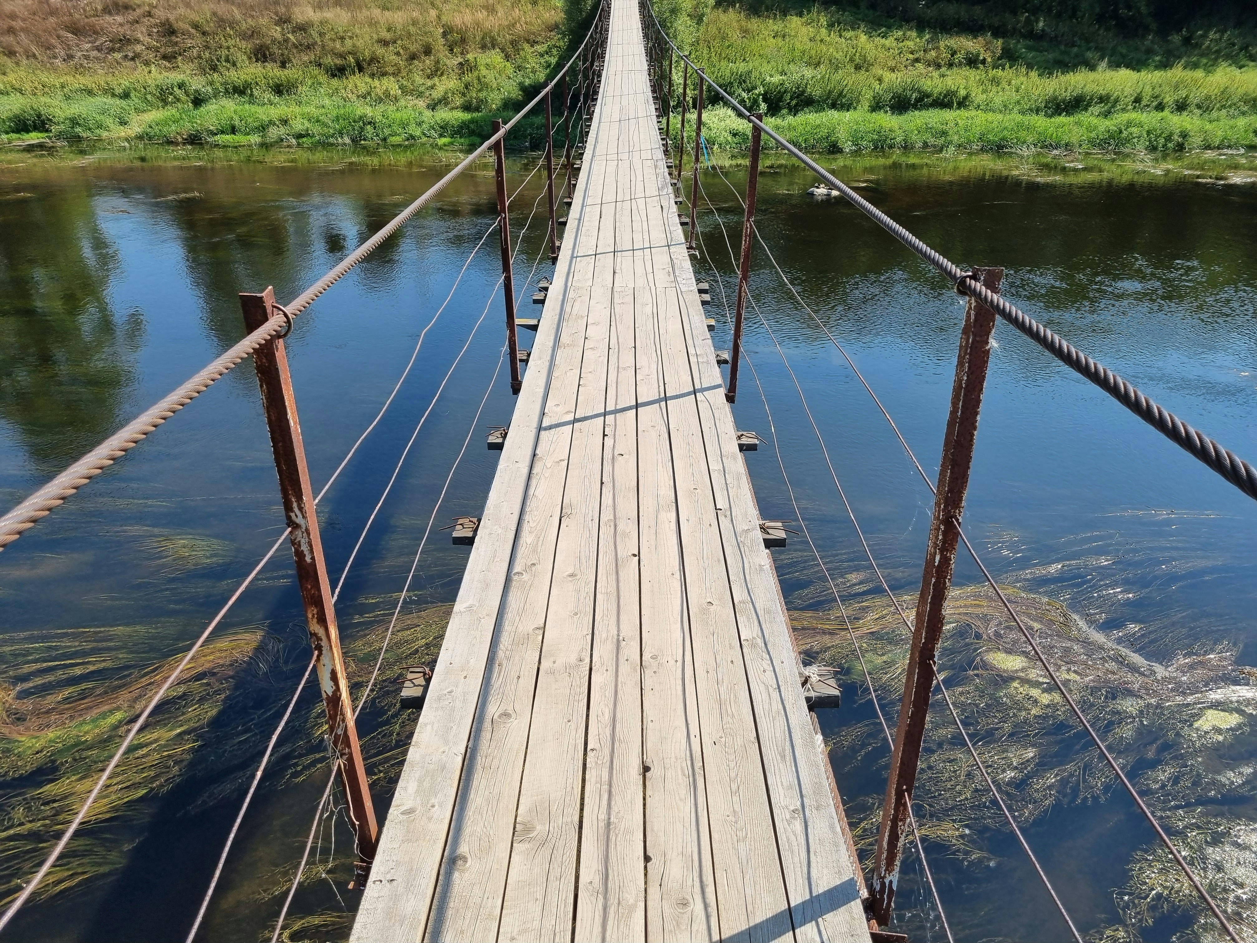 Vanishing Planks: A Wooden Suspension Bridge Over a Quiet River