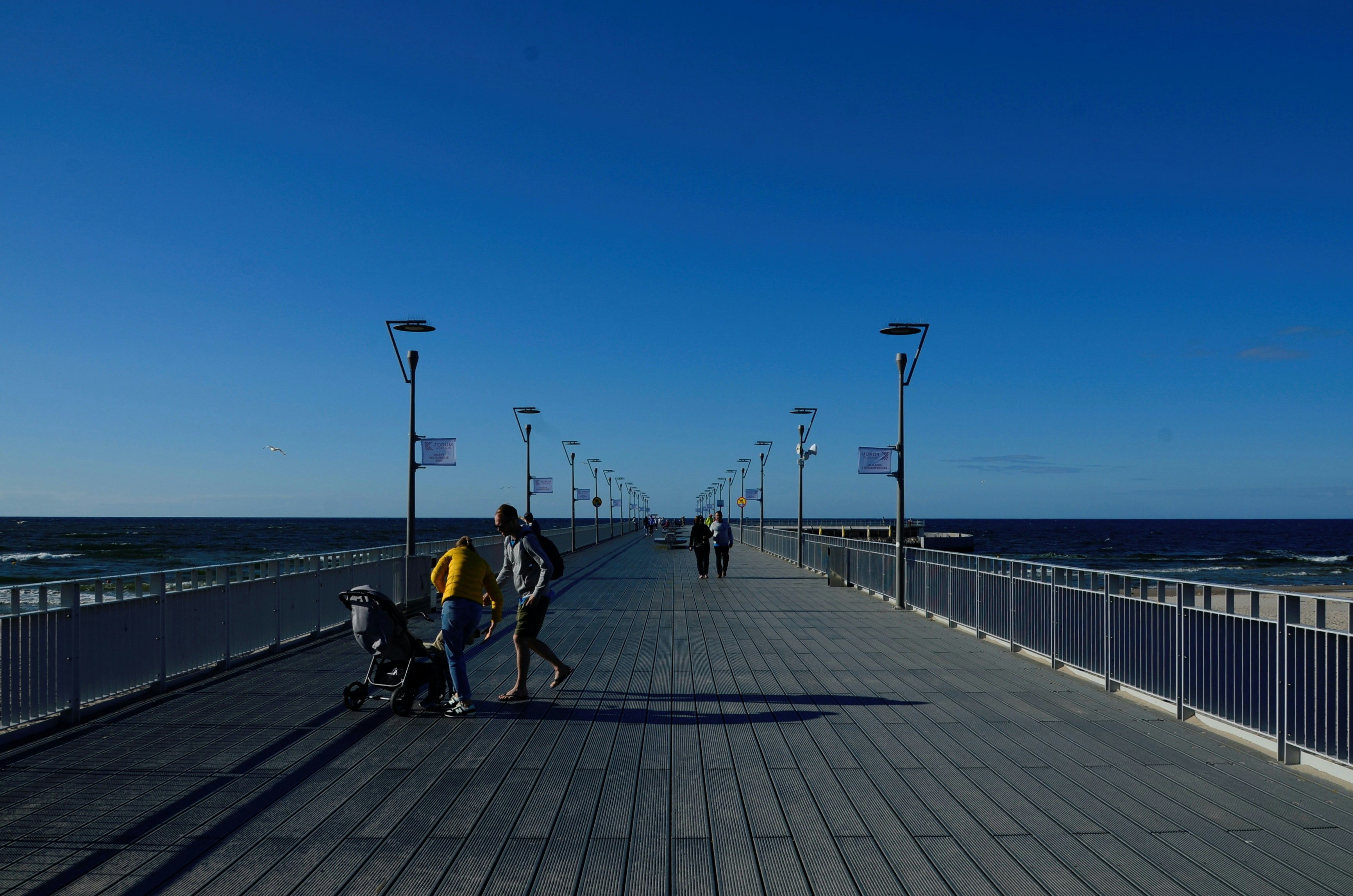 A group of people walking on a boardwalk photo – Free Bulwar jana ...