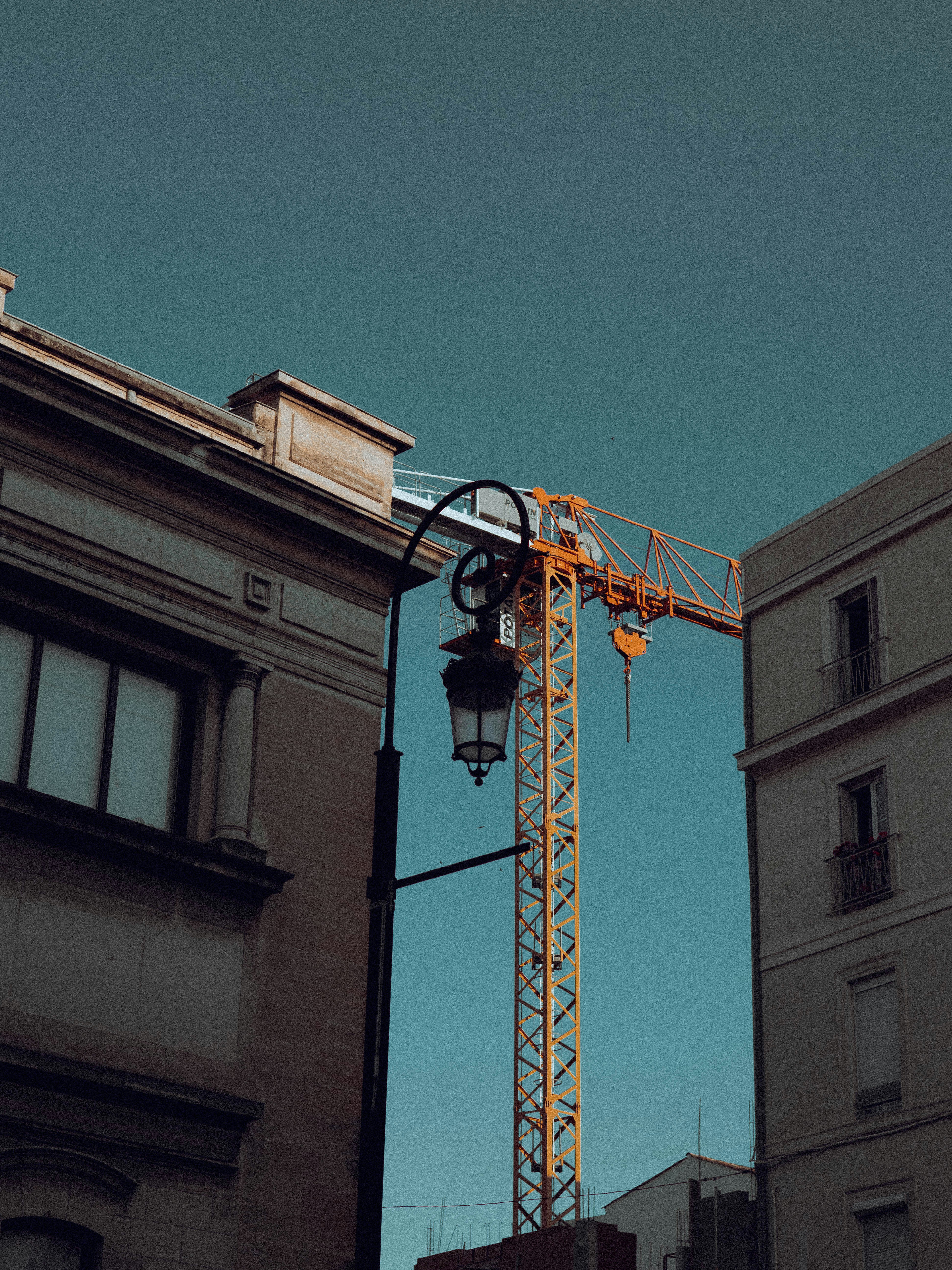 Crane Slices the Sky Between Classical Facades