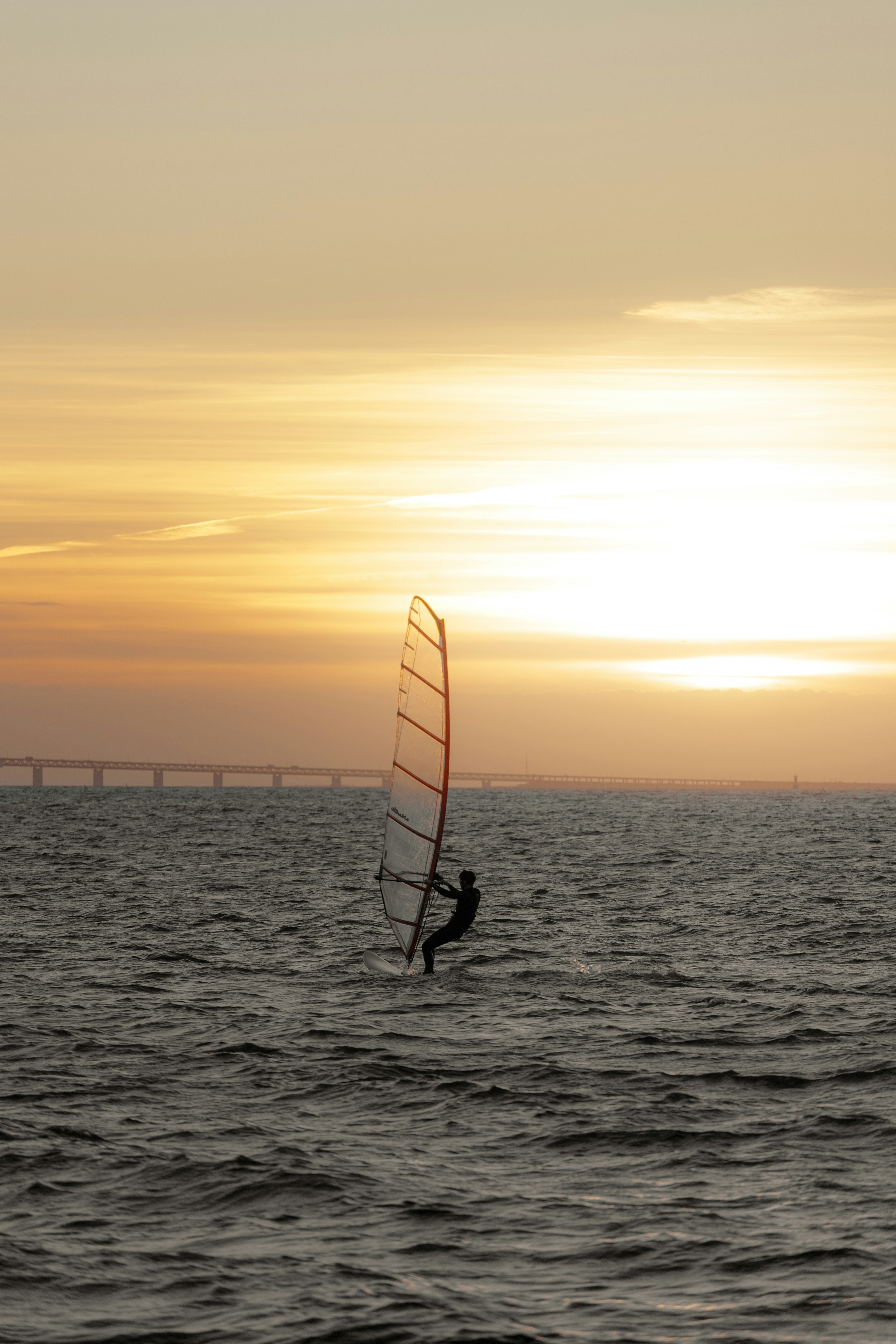 Golden Hour Windsurfer: A Lone Sail Against a Fiery Horizon