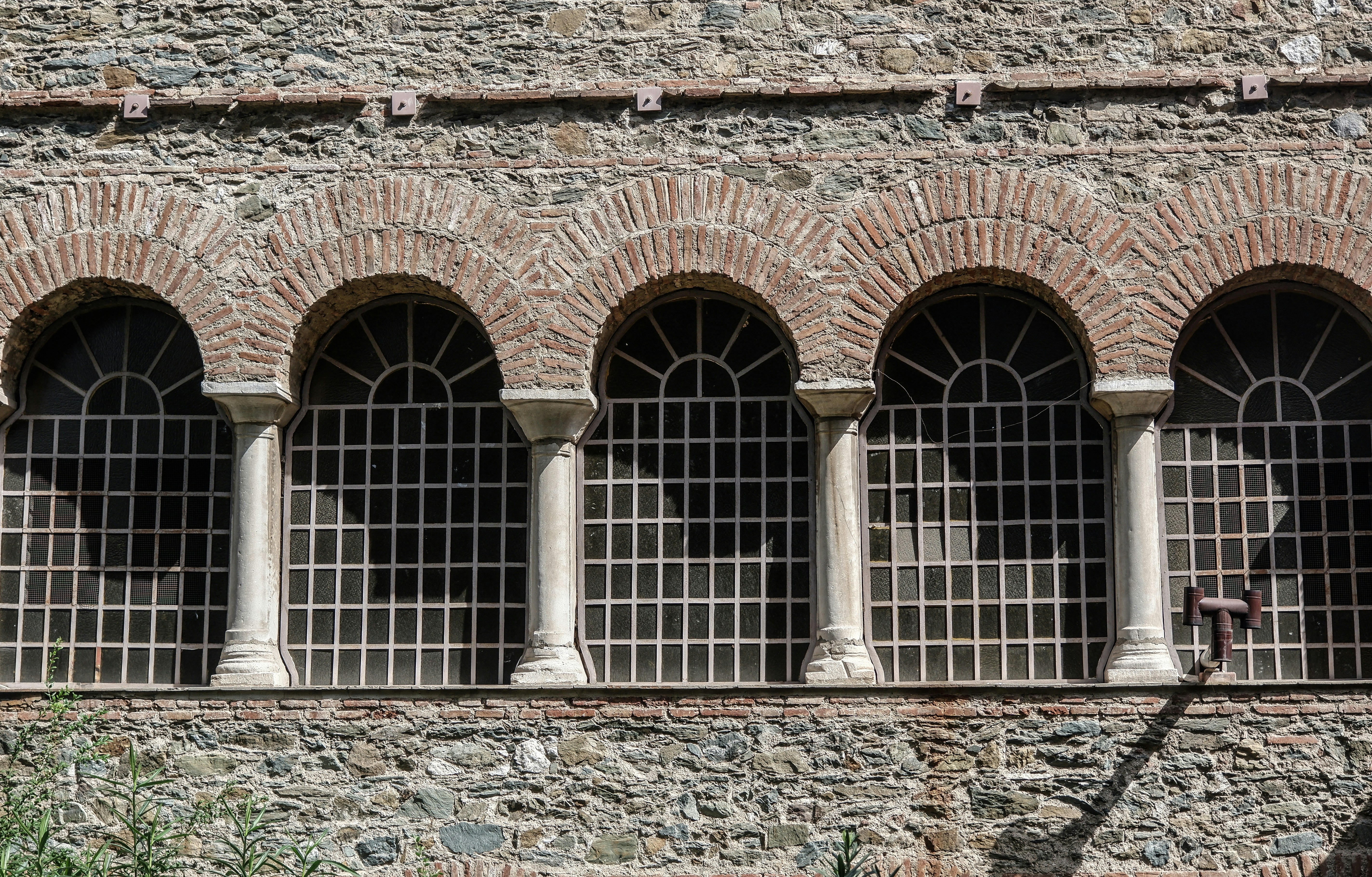 Arched Quiet: Sunlit Brick Archways and Iron Grilles