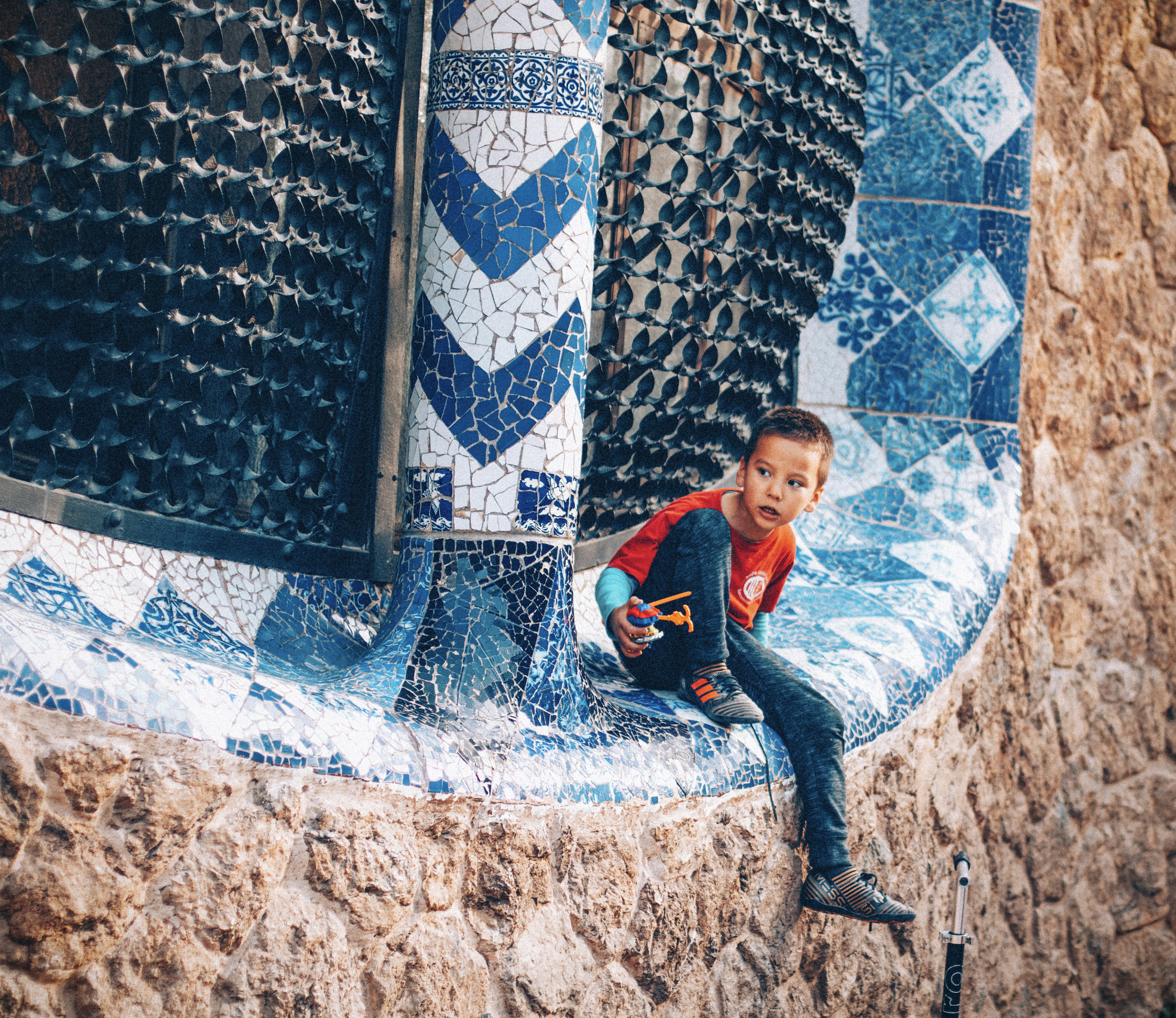 Blue Mosaic Threshold: A Young Boy Pause on a Curved Tile Edge