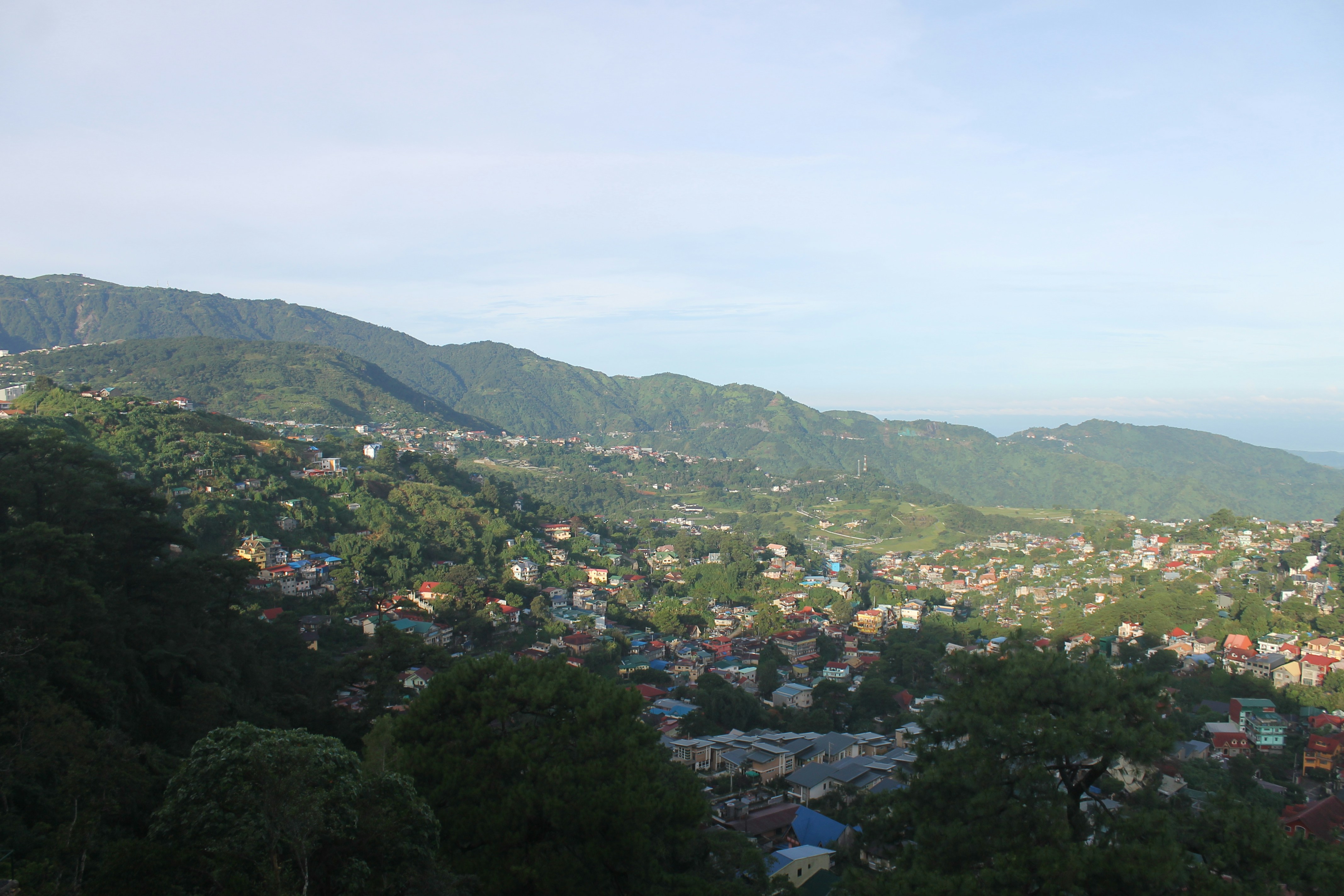 Hillside town nestled among lush green mountains under a clear blue sky.