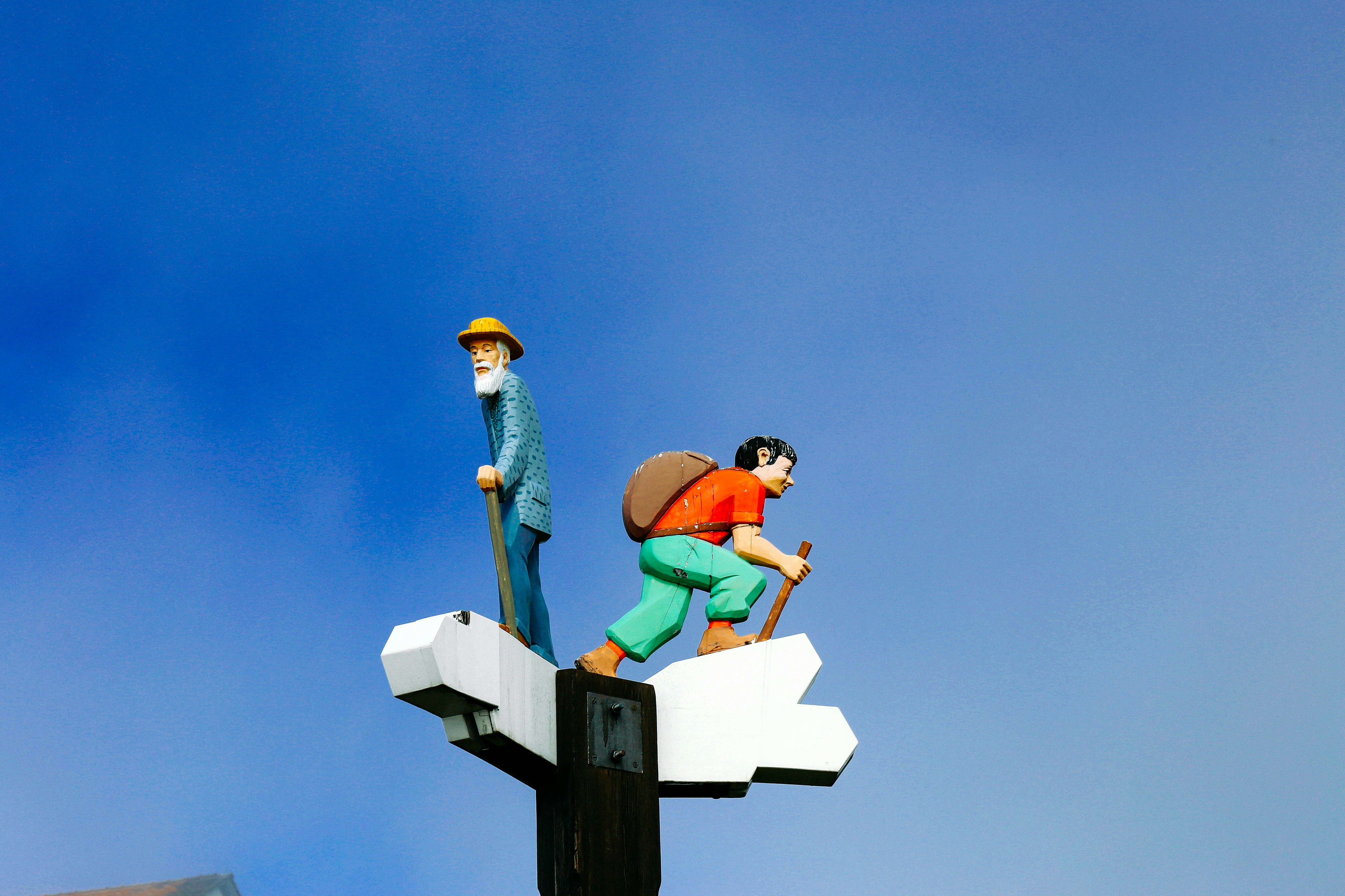 Cloud-Top Carvers: Two Wooden Figures Guard a Skyward Crest