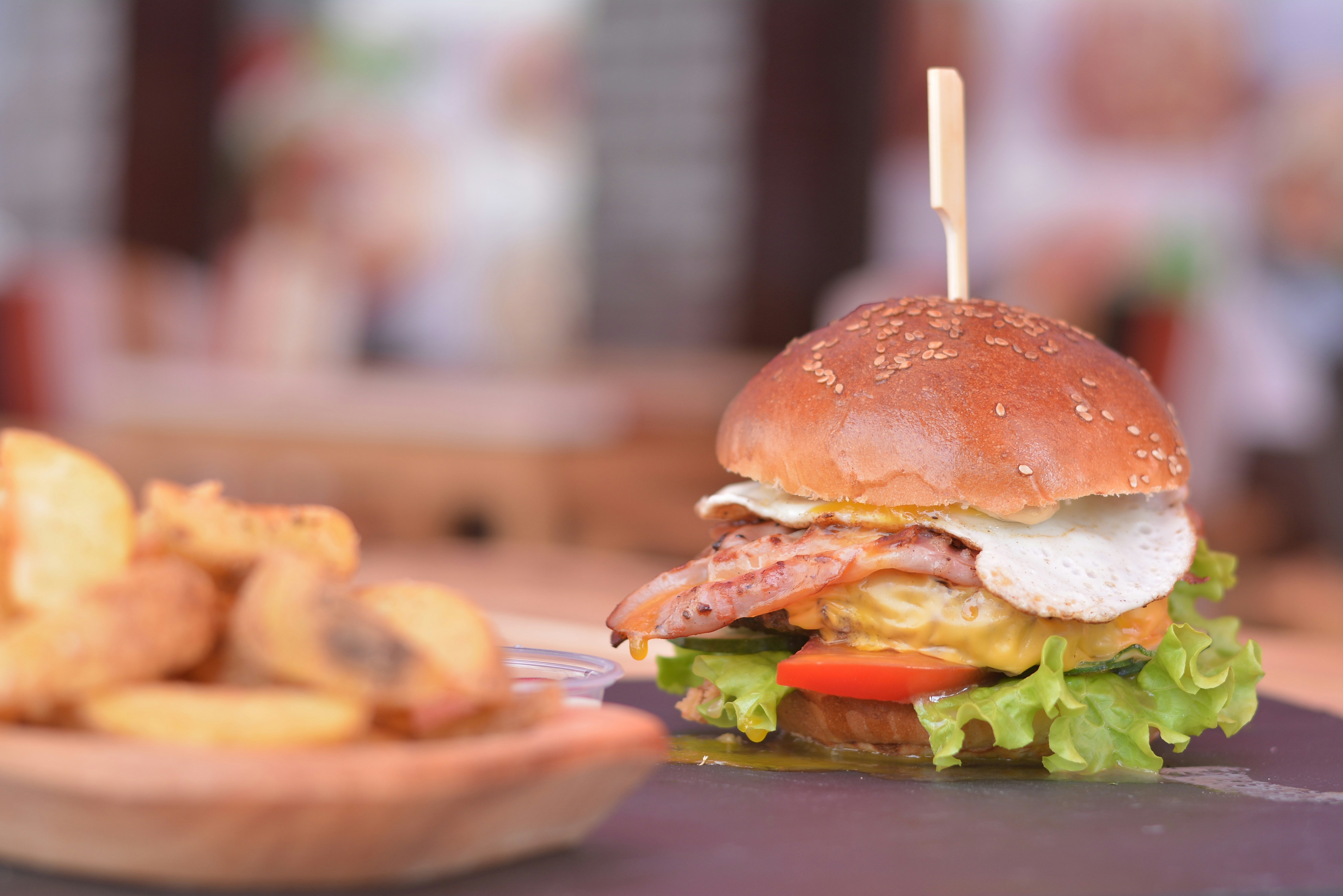 Toothpick-Crowned Burger on a Slate: Fresh Greens and Golden Wedges