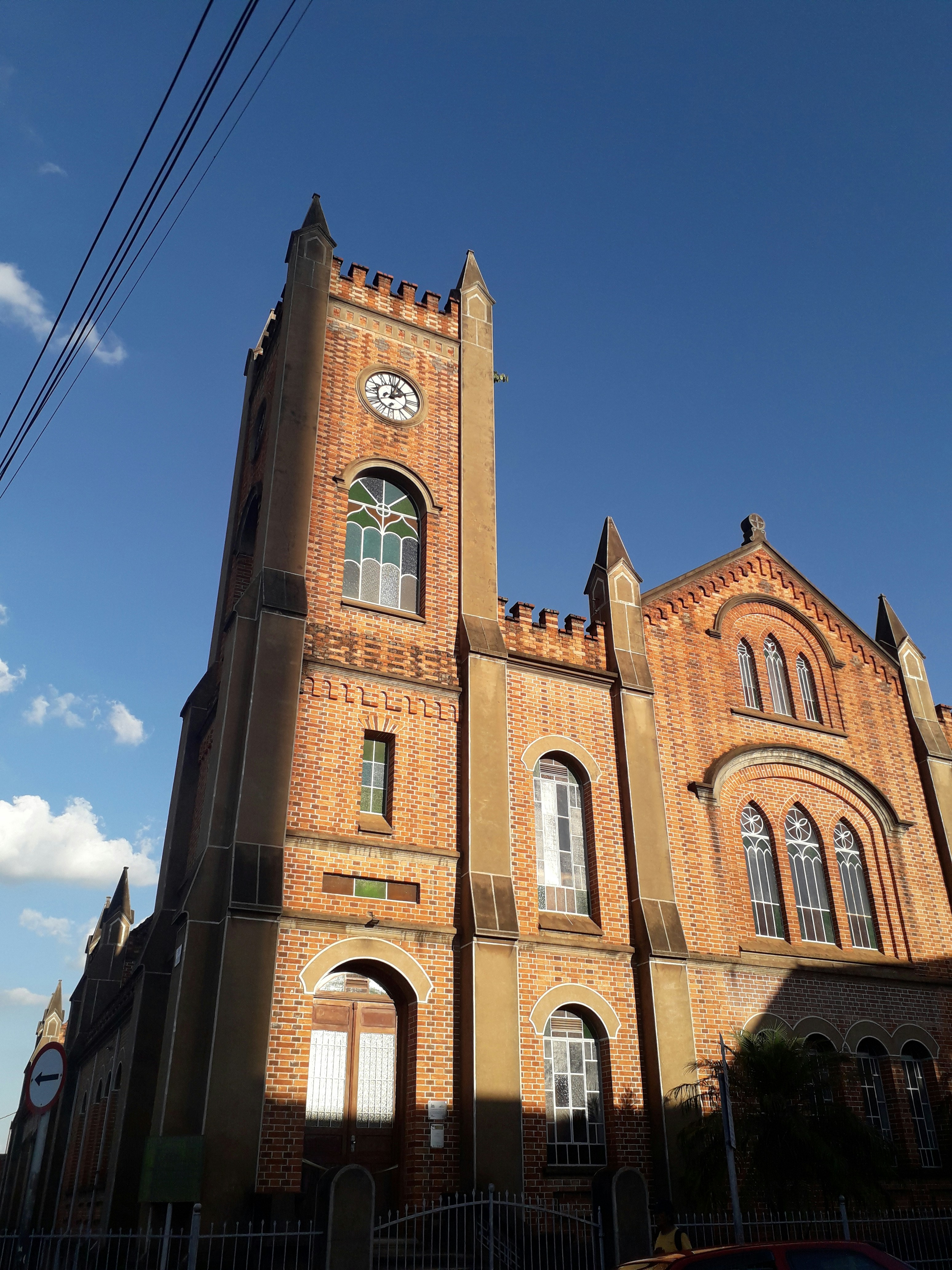 Gothic-style brick church with a clock tower against a clear blue sky.