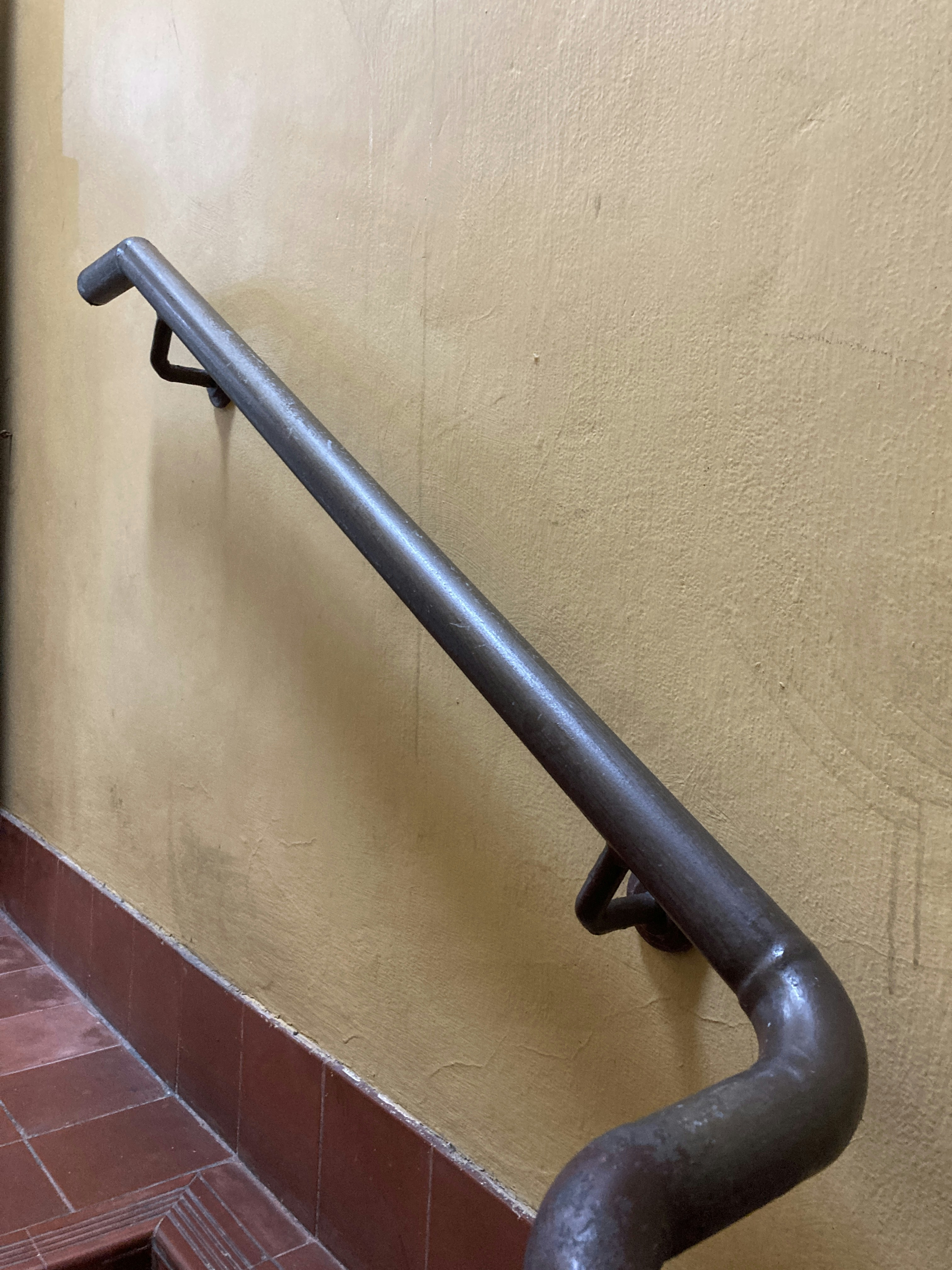 Diagonal Iron: Weathered Handrail in a Sunlit Stairwell