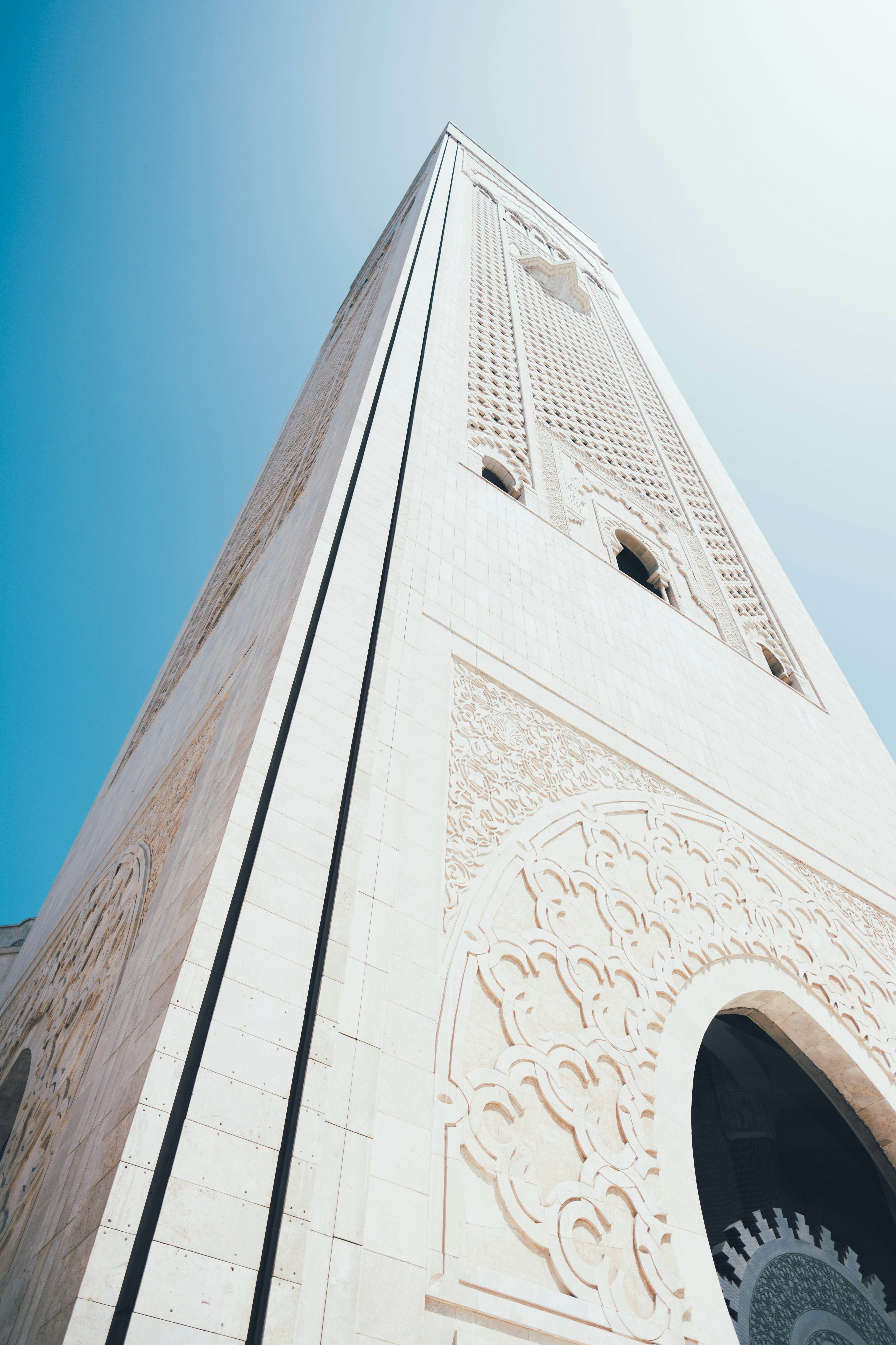 Towering minaret of Hassan II Mosque under a clear blue sky, showcasing intricate architectural details.