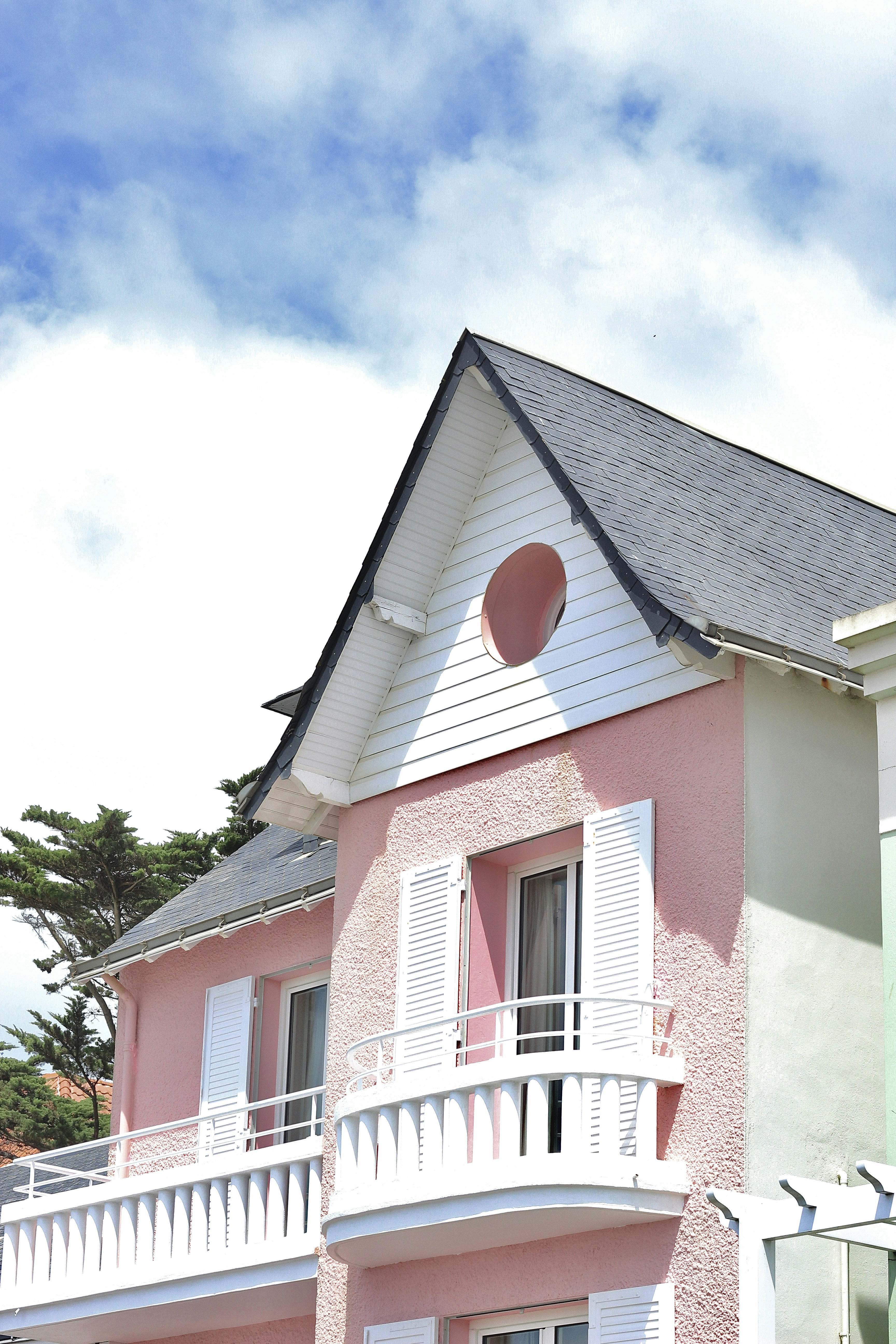 Pastel Pink Villa with a Circular Dormer and White Balcony under a Bright Sky