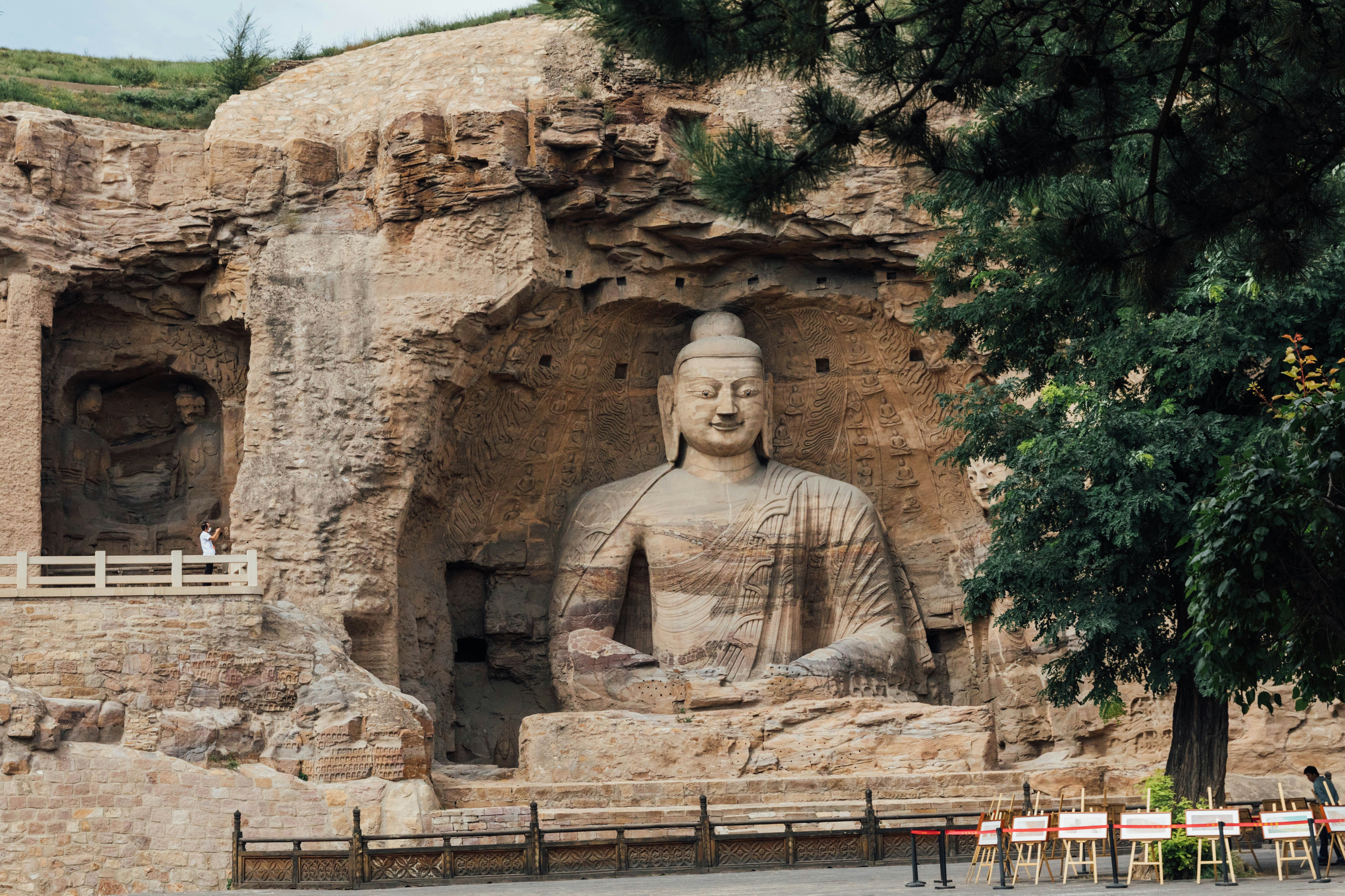Ancient Buddha statue intricately carved into a rock face, surrounded by natural greenery.