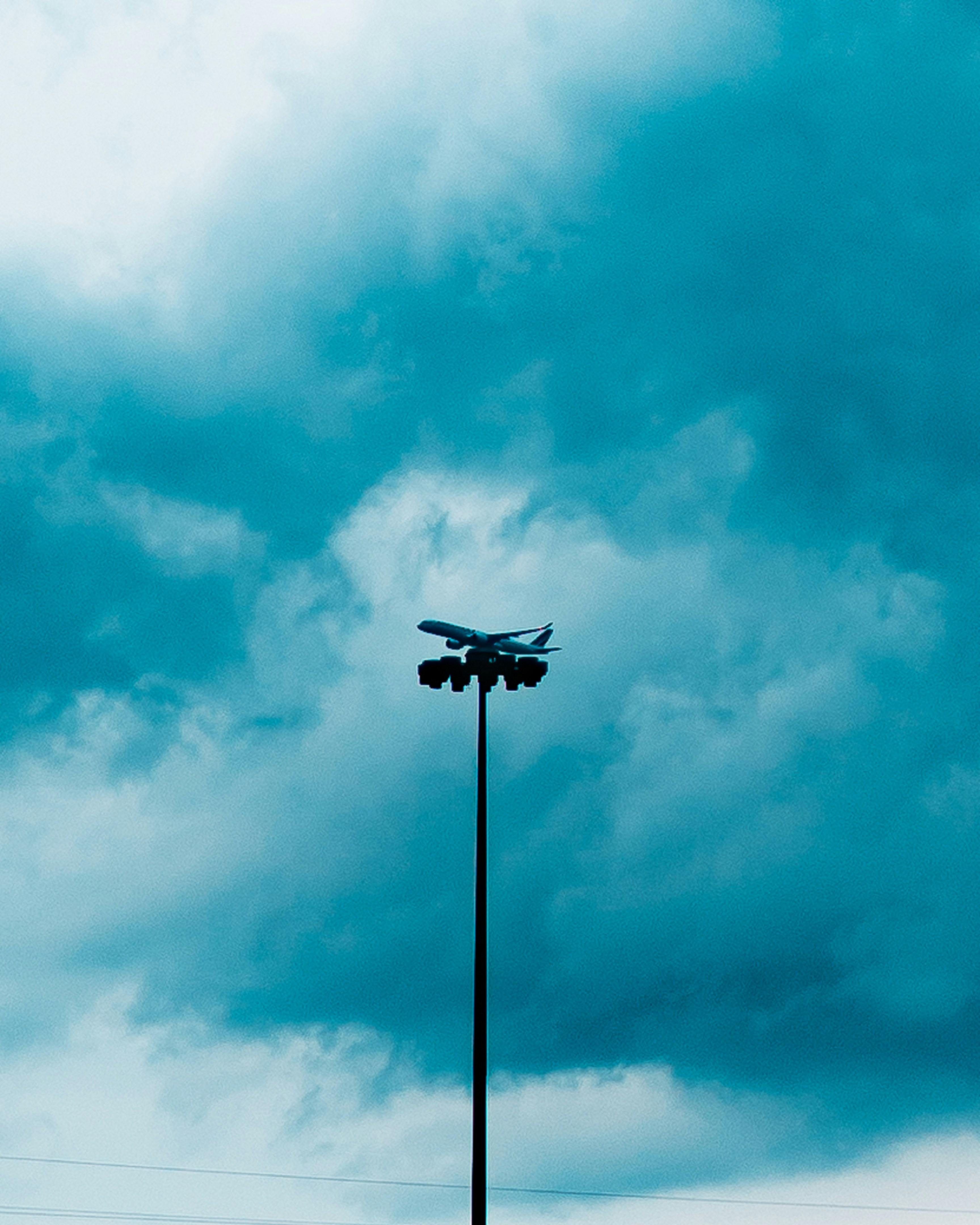 Aircraft perched atop a lone streetlight against a brooding sky