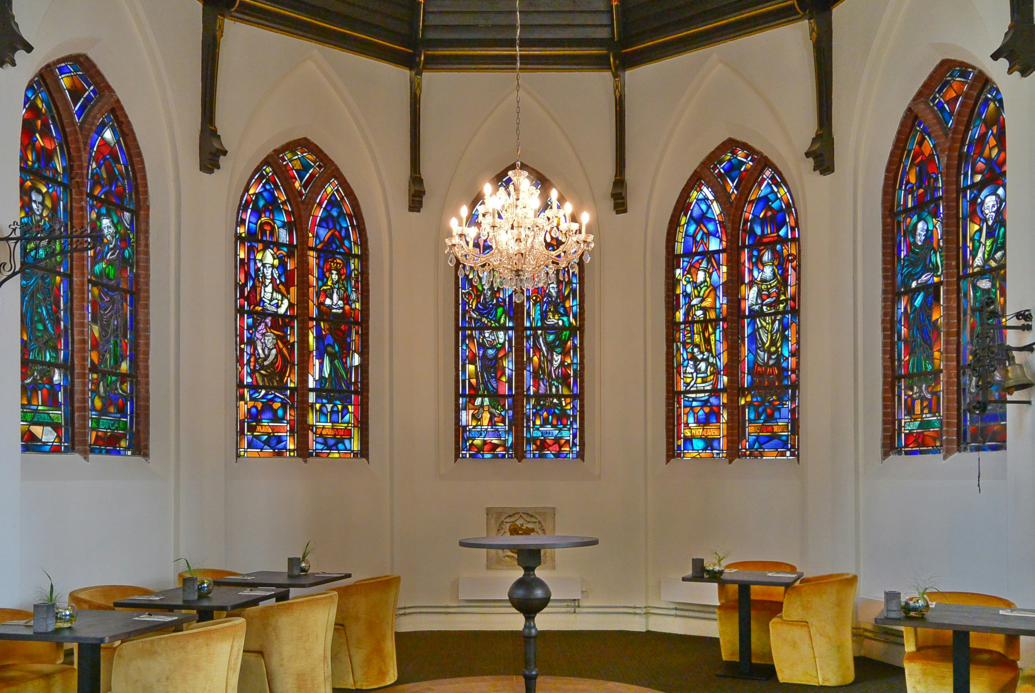 Stained glass windows in a converted church restaurant, featuring vibrant colors and intricate designs.