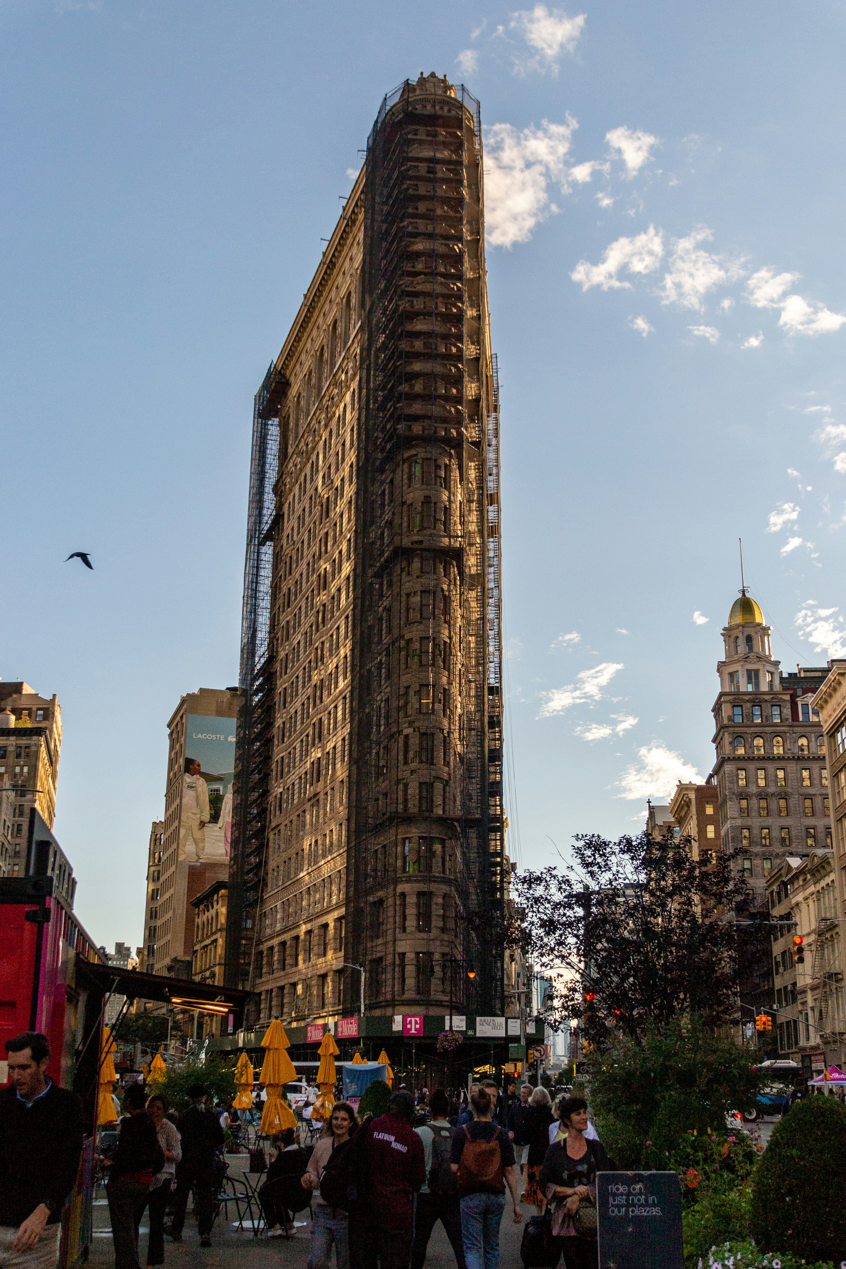 Historic flatiron building framed by bustling street life and vibrant outdoor seating. The scene captures the essence of city culture.