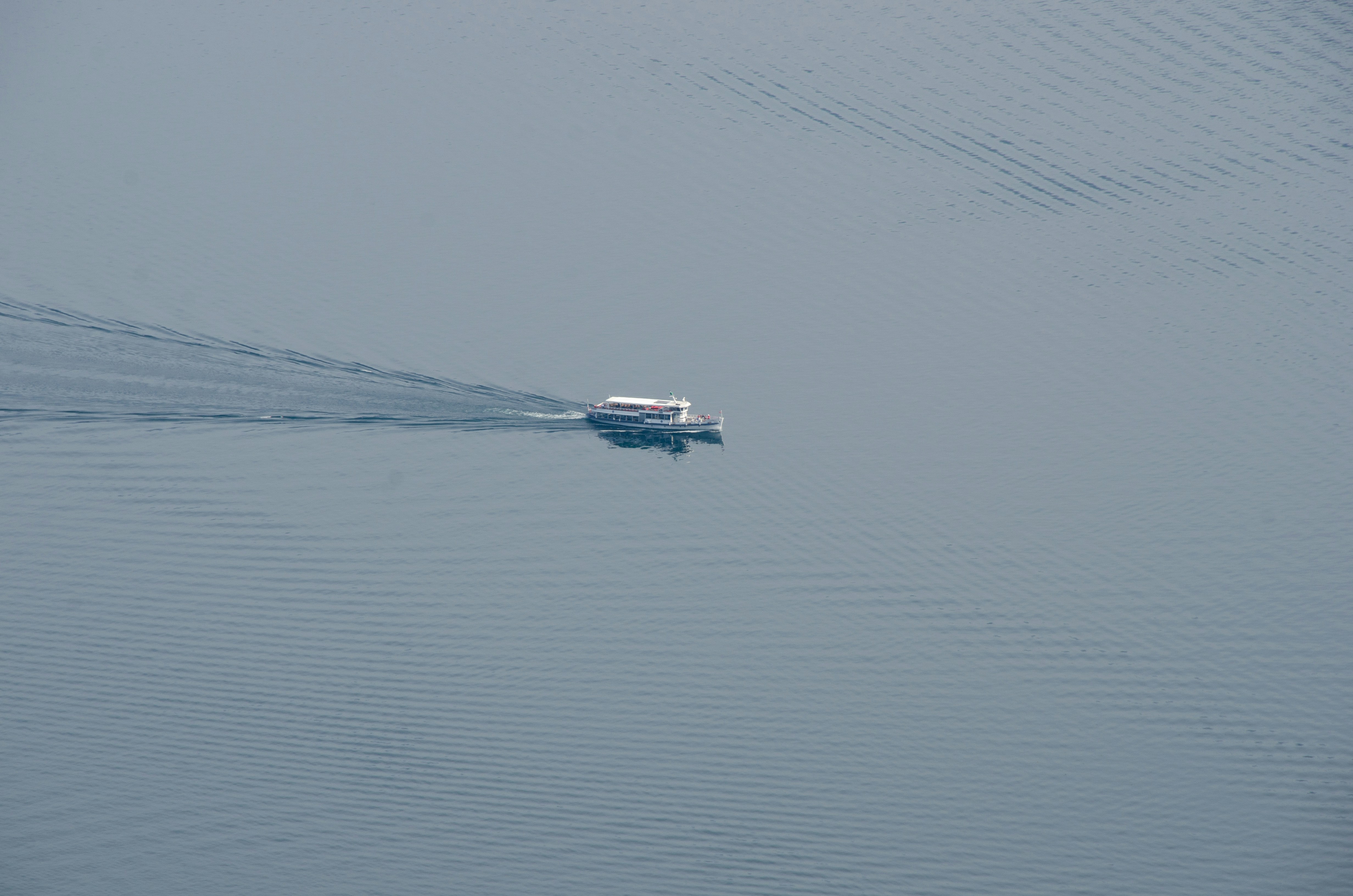 Glassy Blue Wake: A Small Boat Traces a Quiet Path Across Calm Water