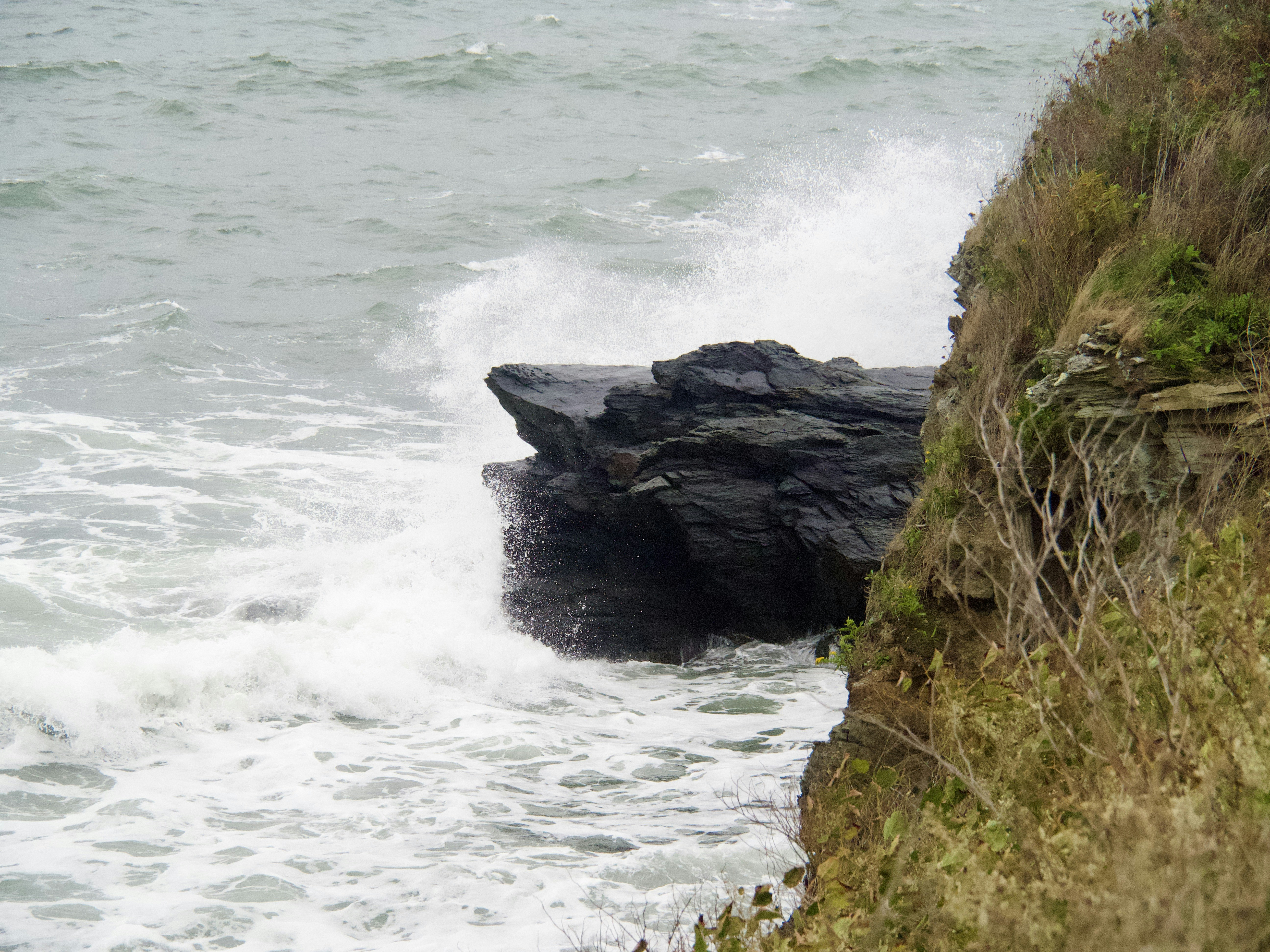 Waves crashing against a rugged cliffside, highlighting the dynamic interaction between water and rock. The scene captures the raw power of nature.