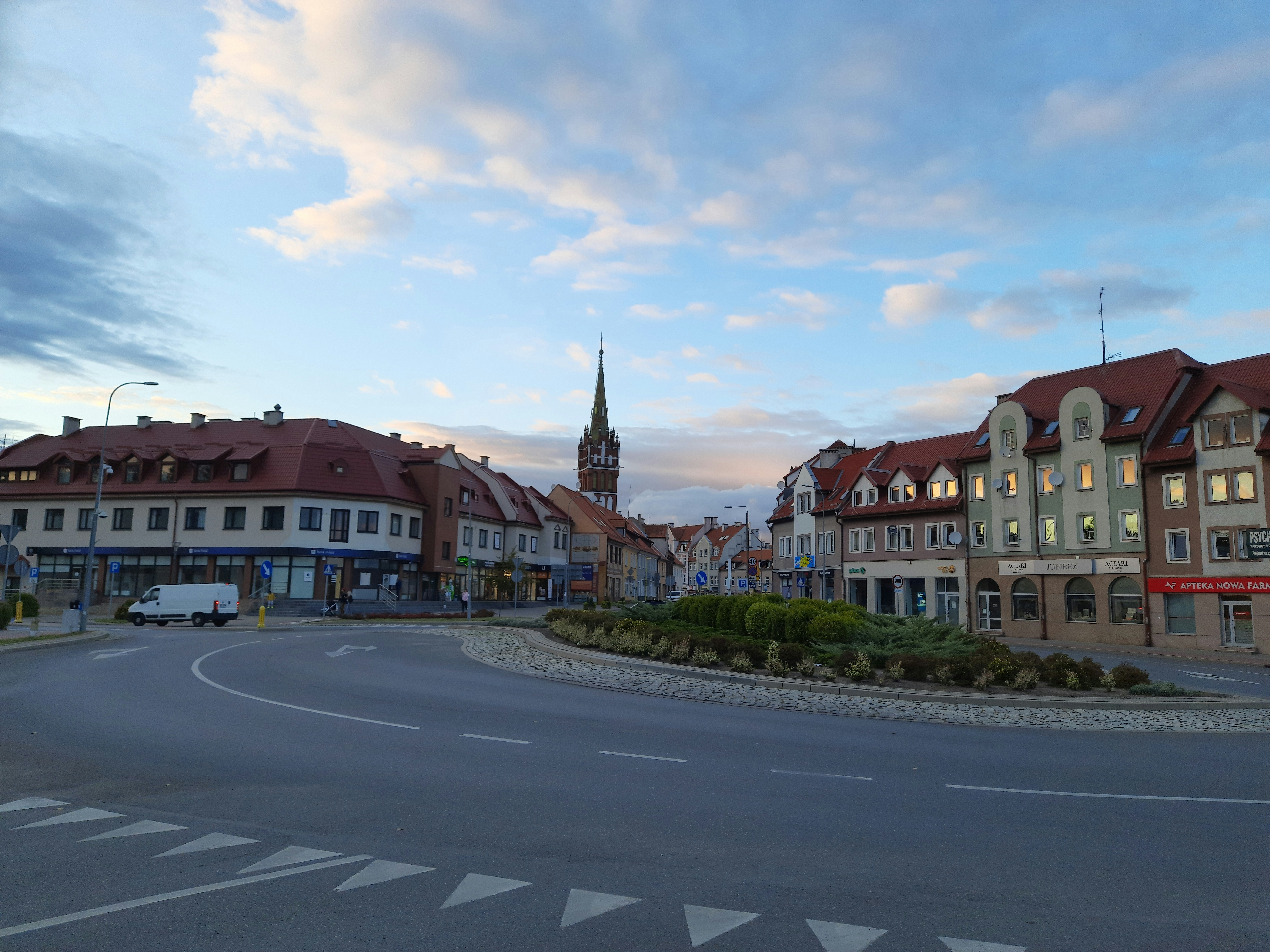 Charming town square with historic buildings and a clock tower at dusk, showcasing a blend of architecture and vibrant sky colors.
