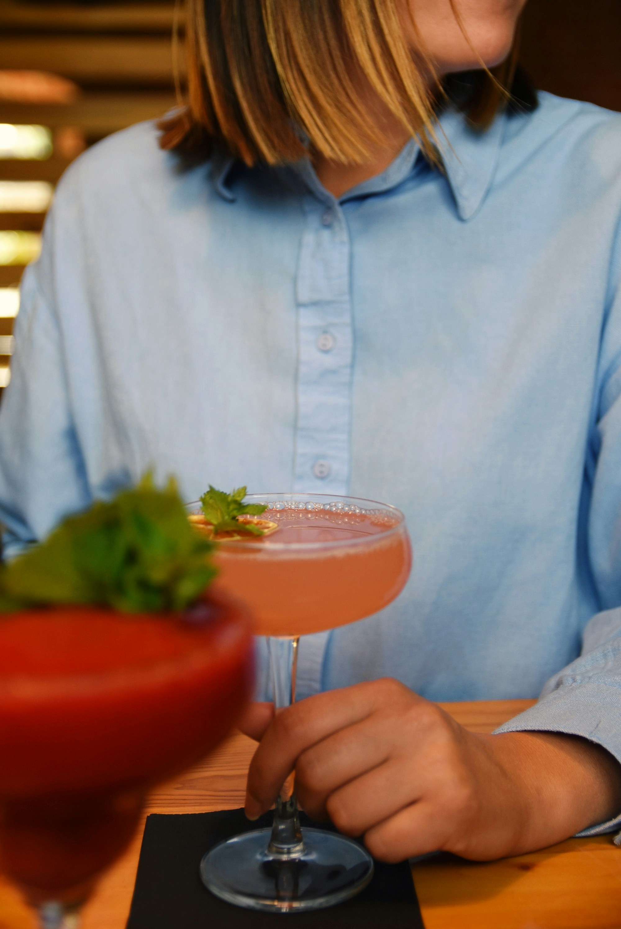 Pink cocktail glow: a close-up of a person at a bar with two drinks