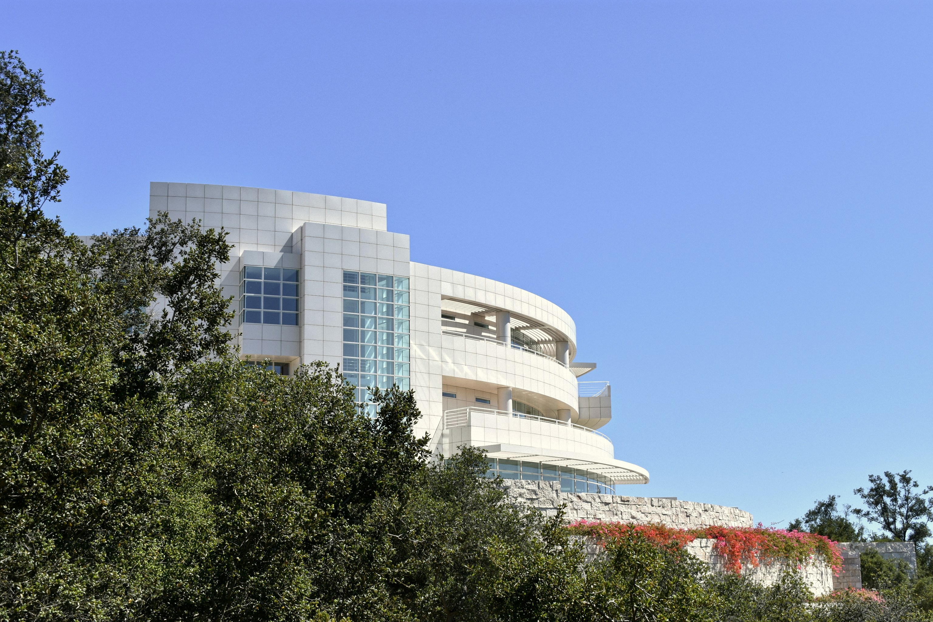 Modern architecture of a building surrounded by lush greenery under a clear blue sky.
