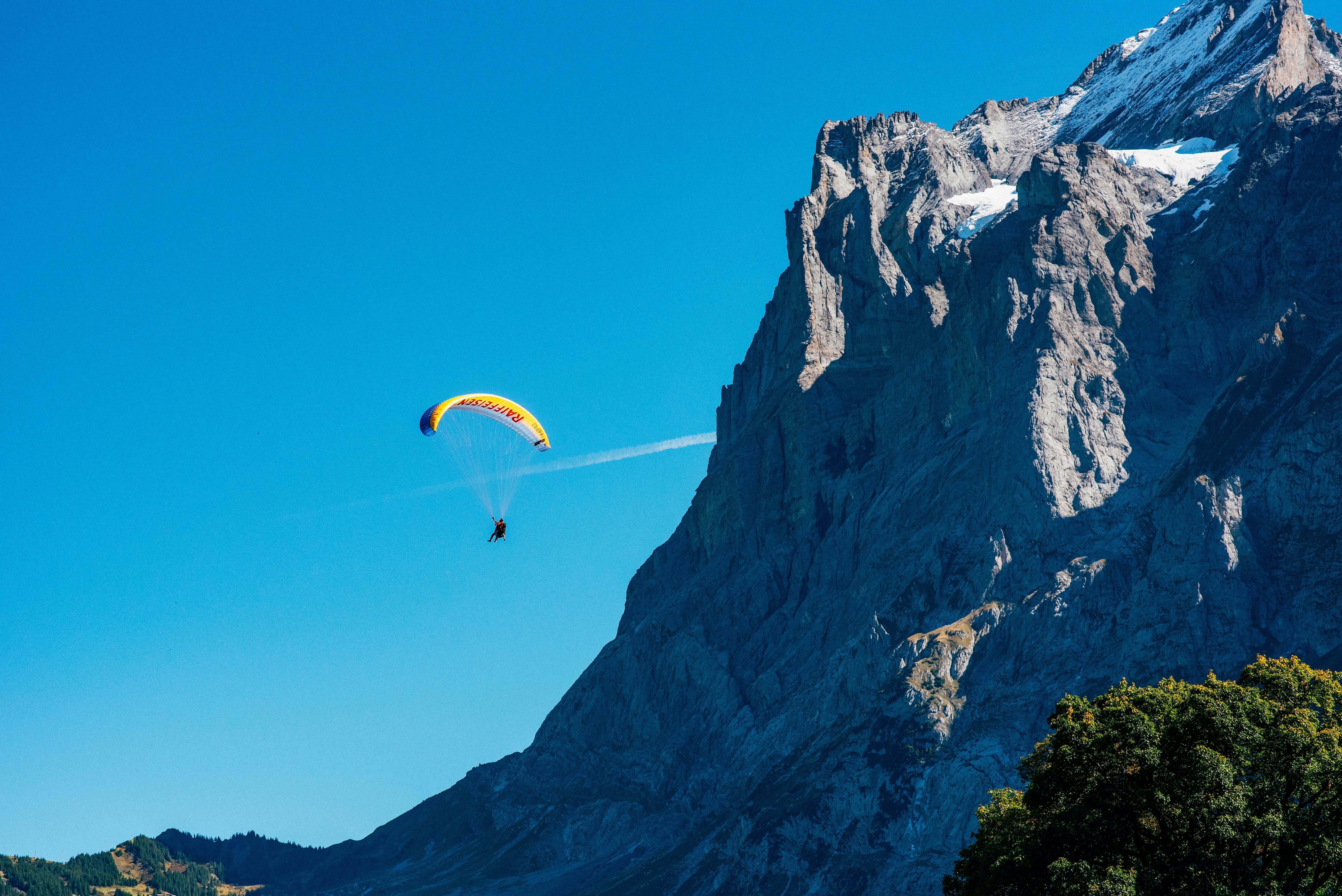 Golden Paraglider Traces a Bright Arc Across Jagged Alpine Face
