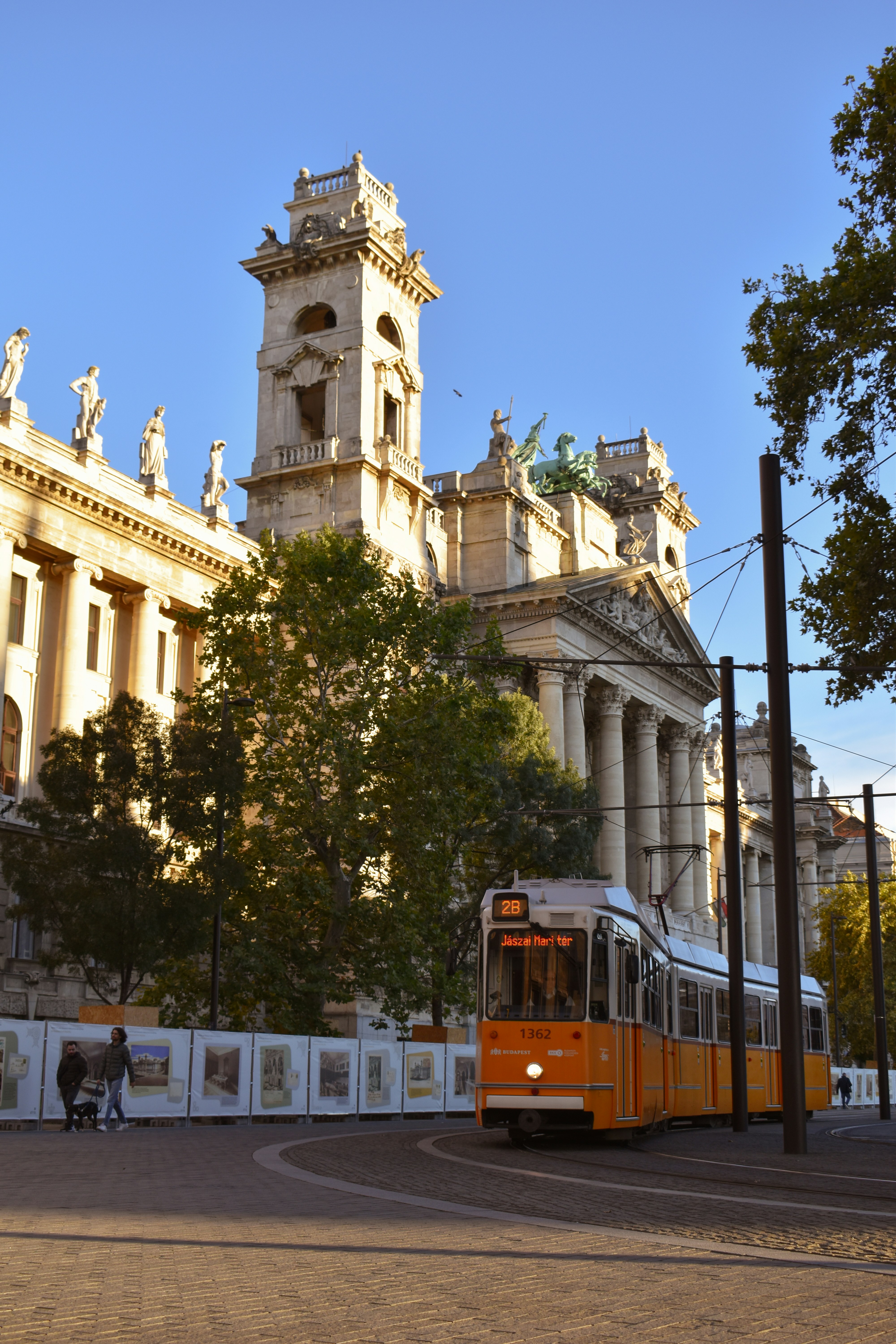 Azure skies over a grand entry: a city tram near classical arches