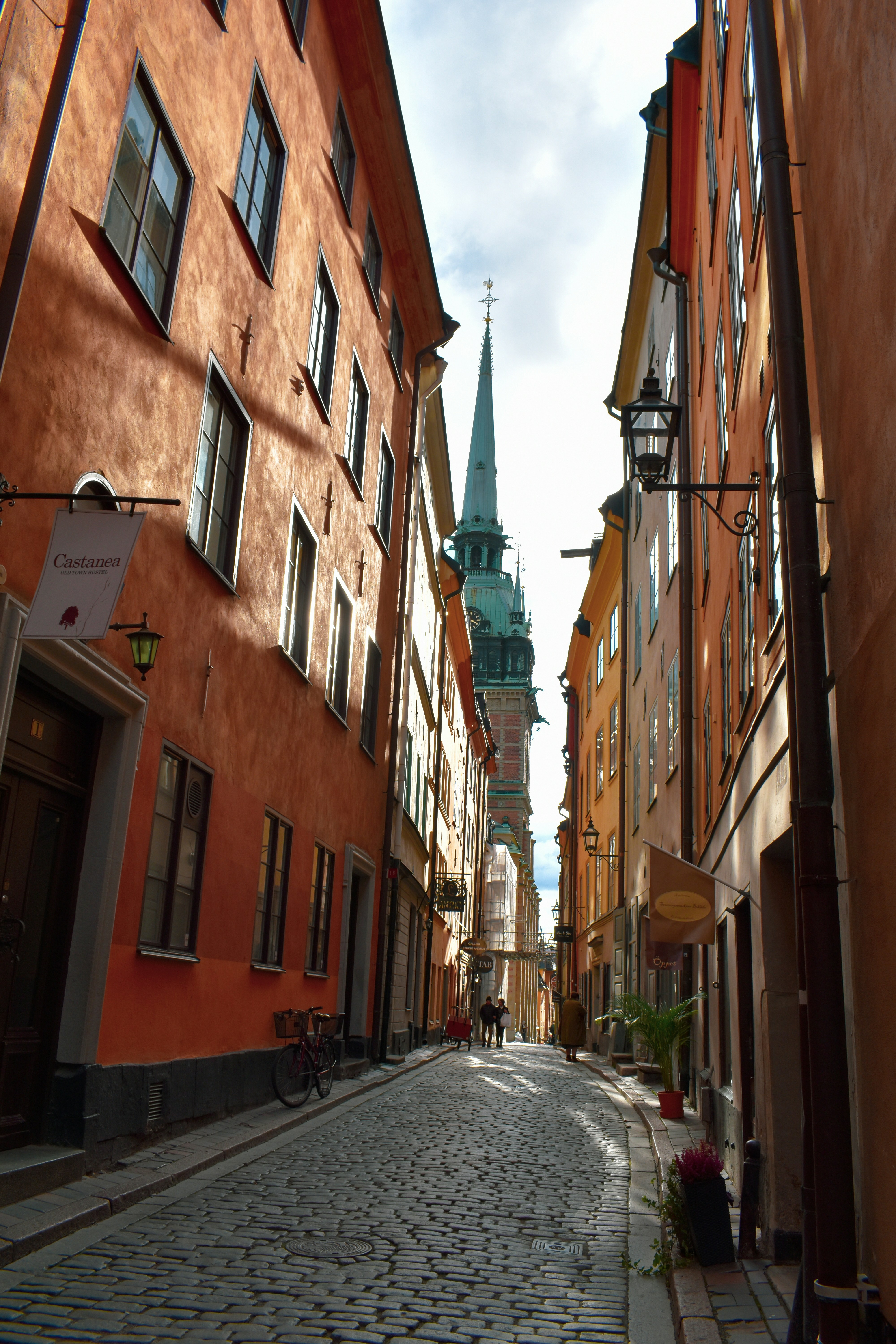 Alley Toward the Turquoise Spire: Sunlit Facades and a Quiet European Street