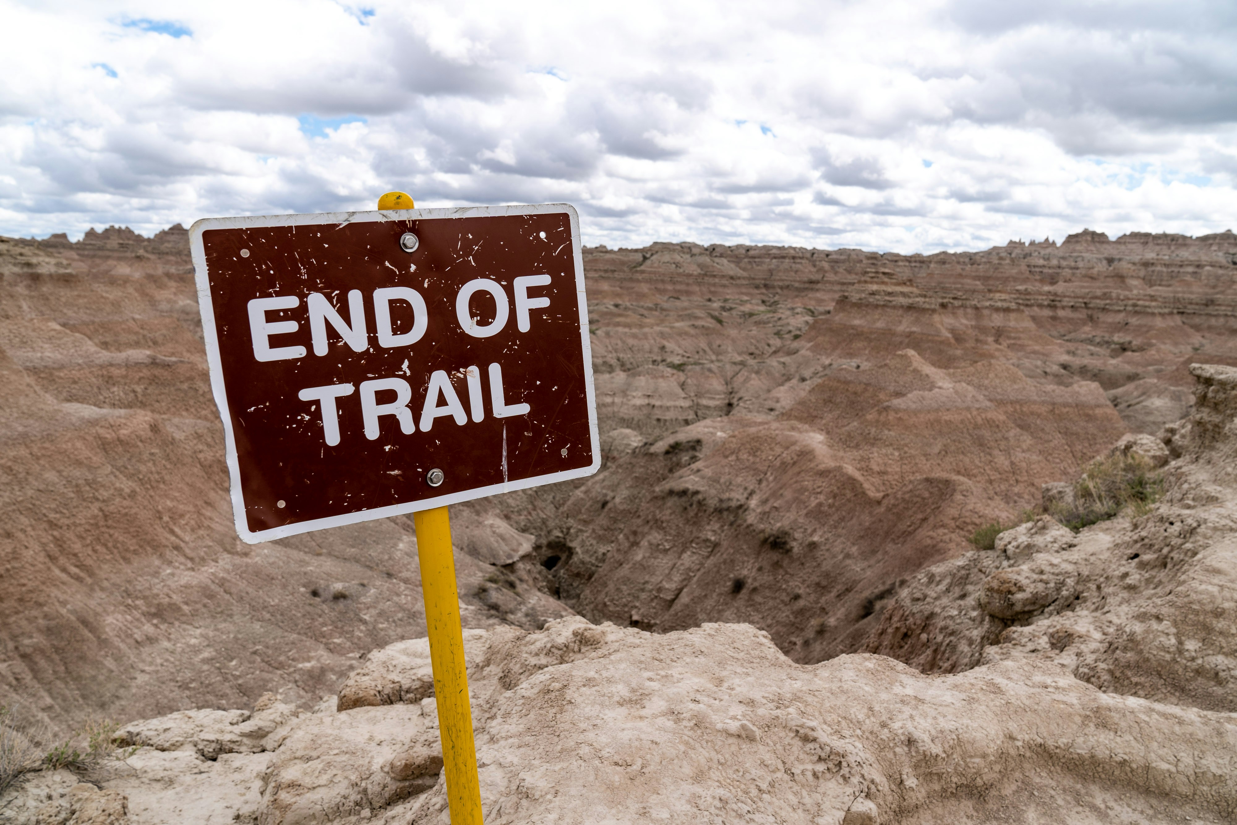 Weathered 'End of Trail' Sign Over a Desolate Canyon
