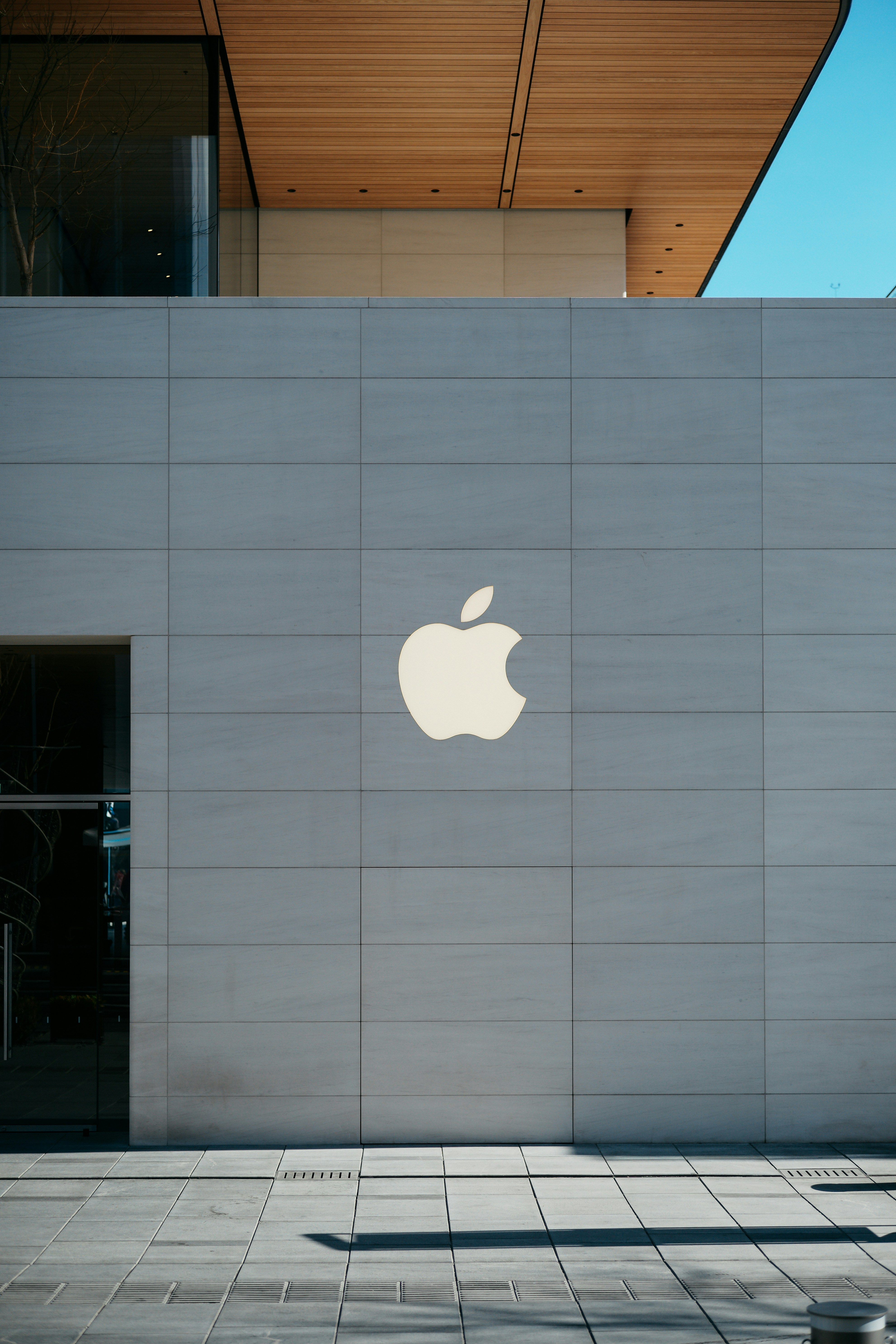 Apple logo illuminated on a sleek stone wall of a contemporary building, showcasing modern architecture.