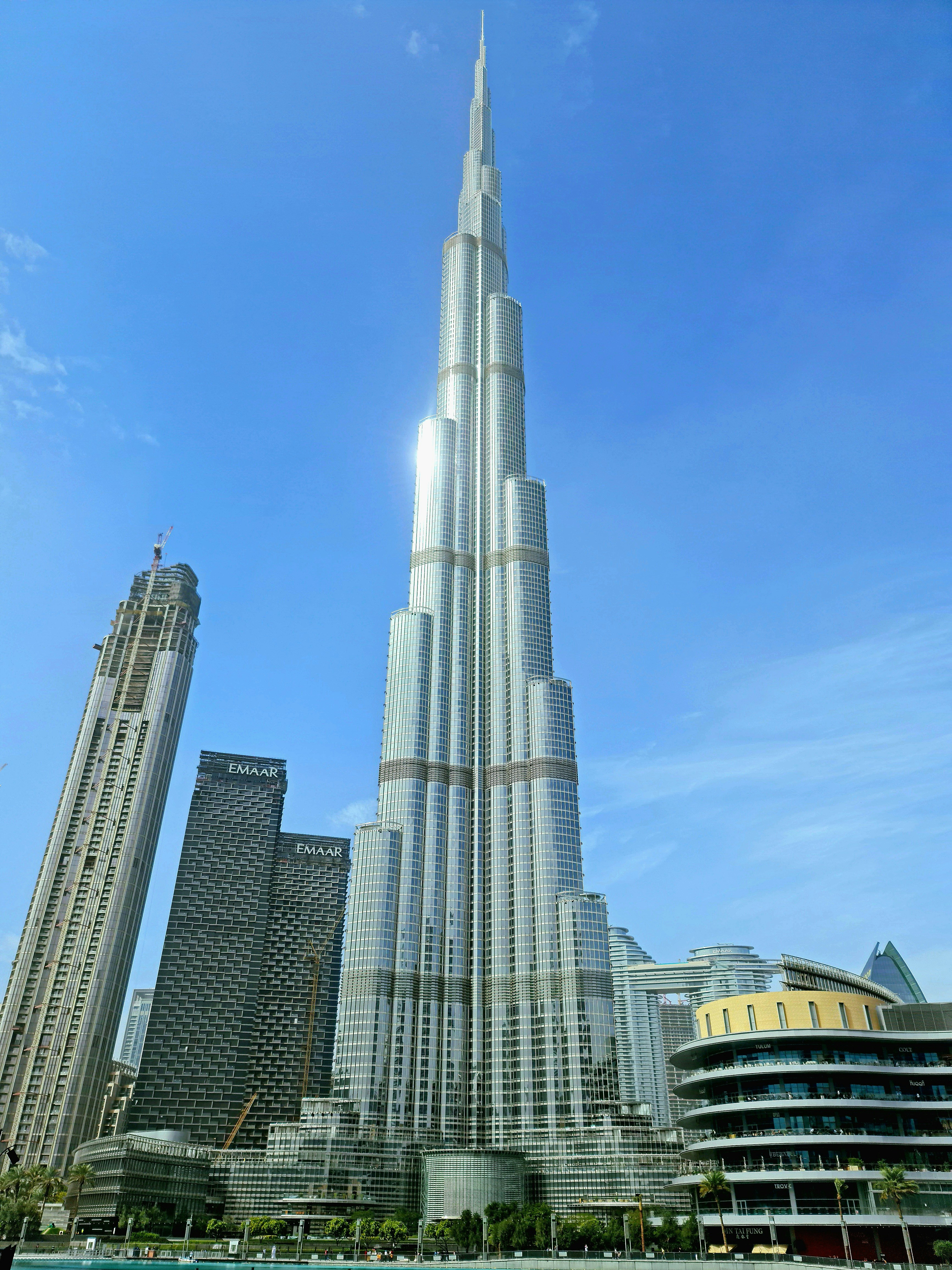 Burj Khalifa towering against a clear blue sky, surrounded by contemporary buildings in Dubai. A testament to architectural innovation.