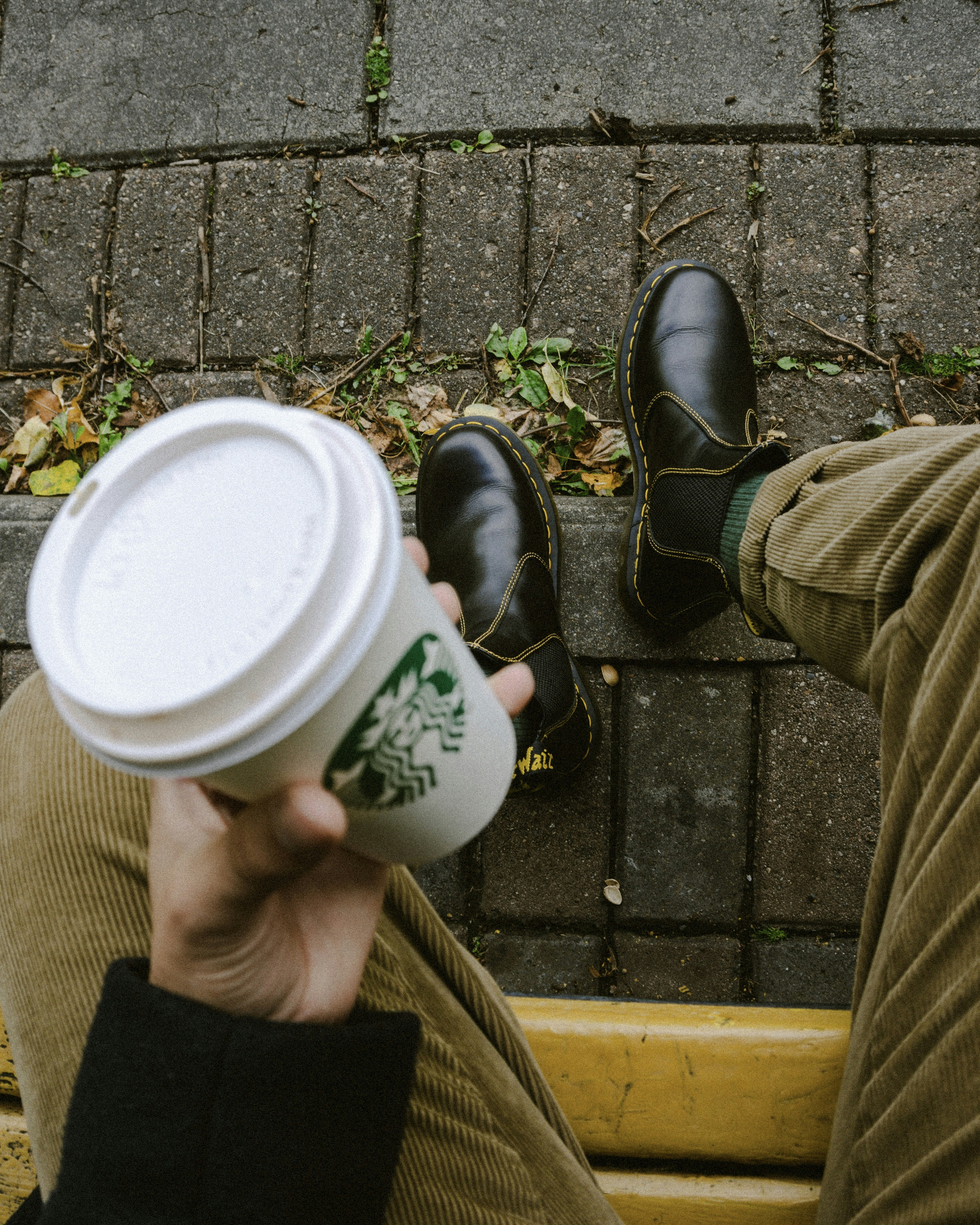 Ground-Level Pause: A Starbucks Cup Anchors a Moment on Weathered Pavement