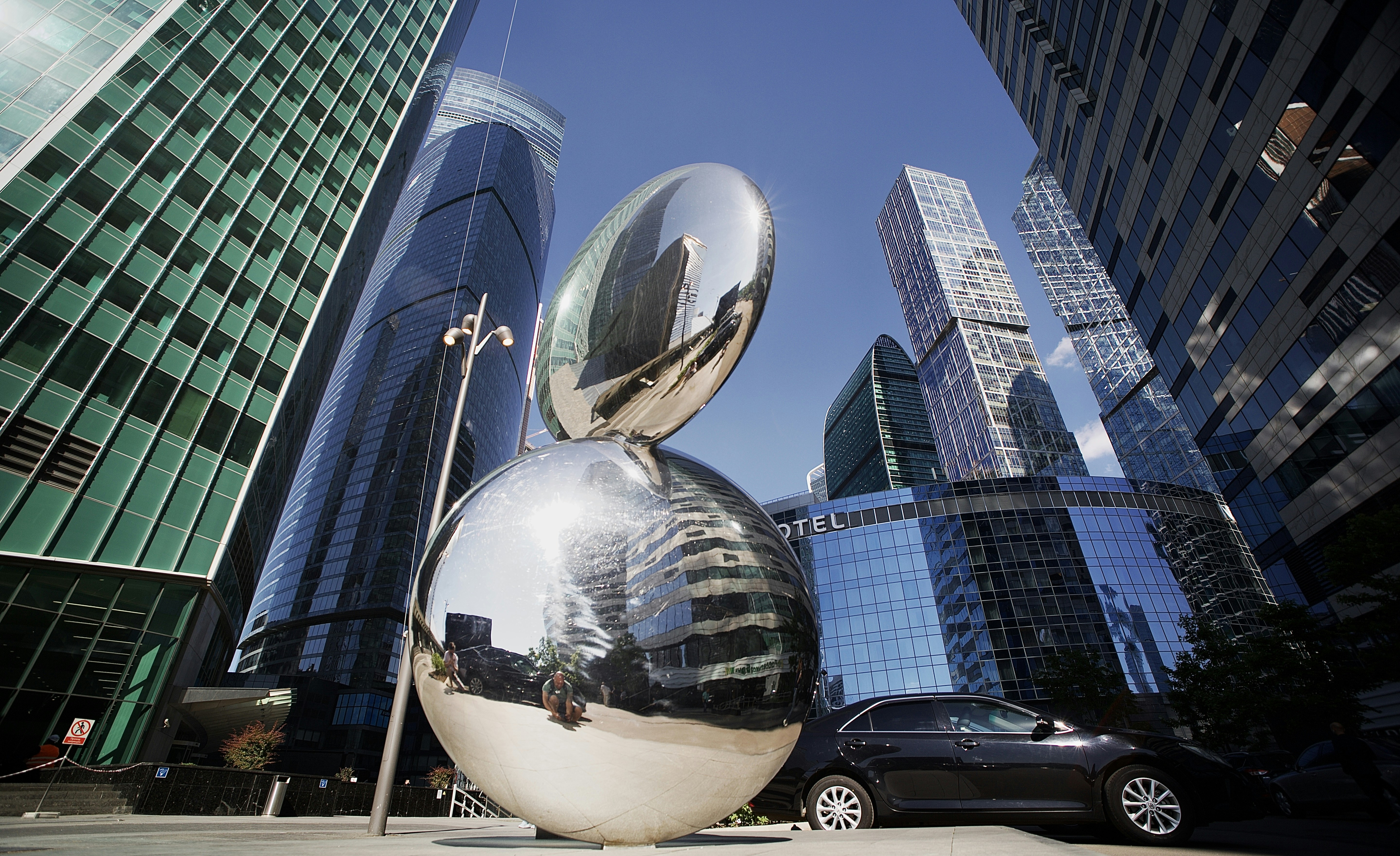 A large silver ball in front of a large building photo – Free City ...