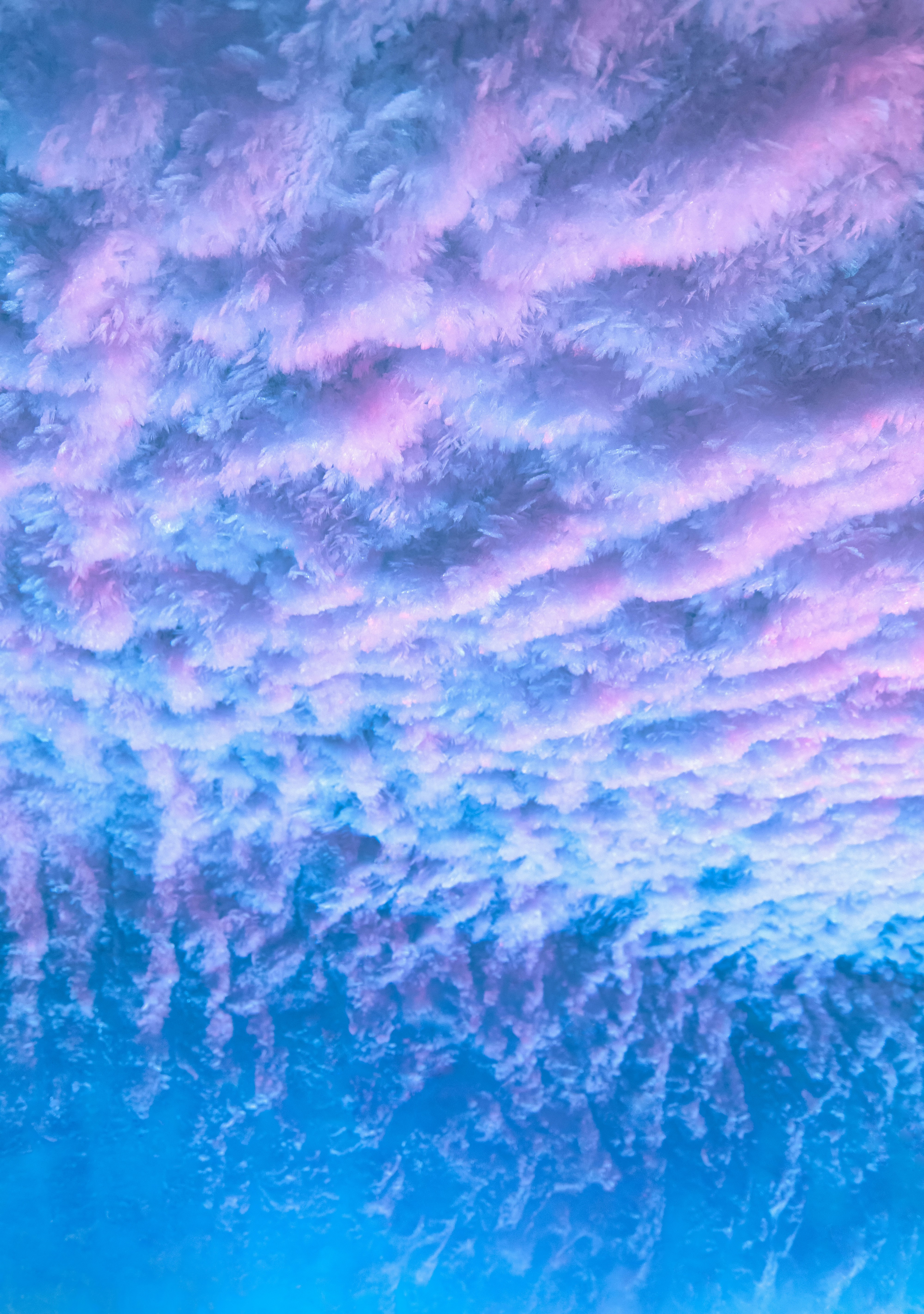 A mesmerizing display of textured clouds illuminated in soft hues of pink and blue, creating a serene atmosphere.