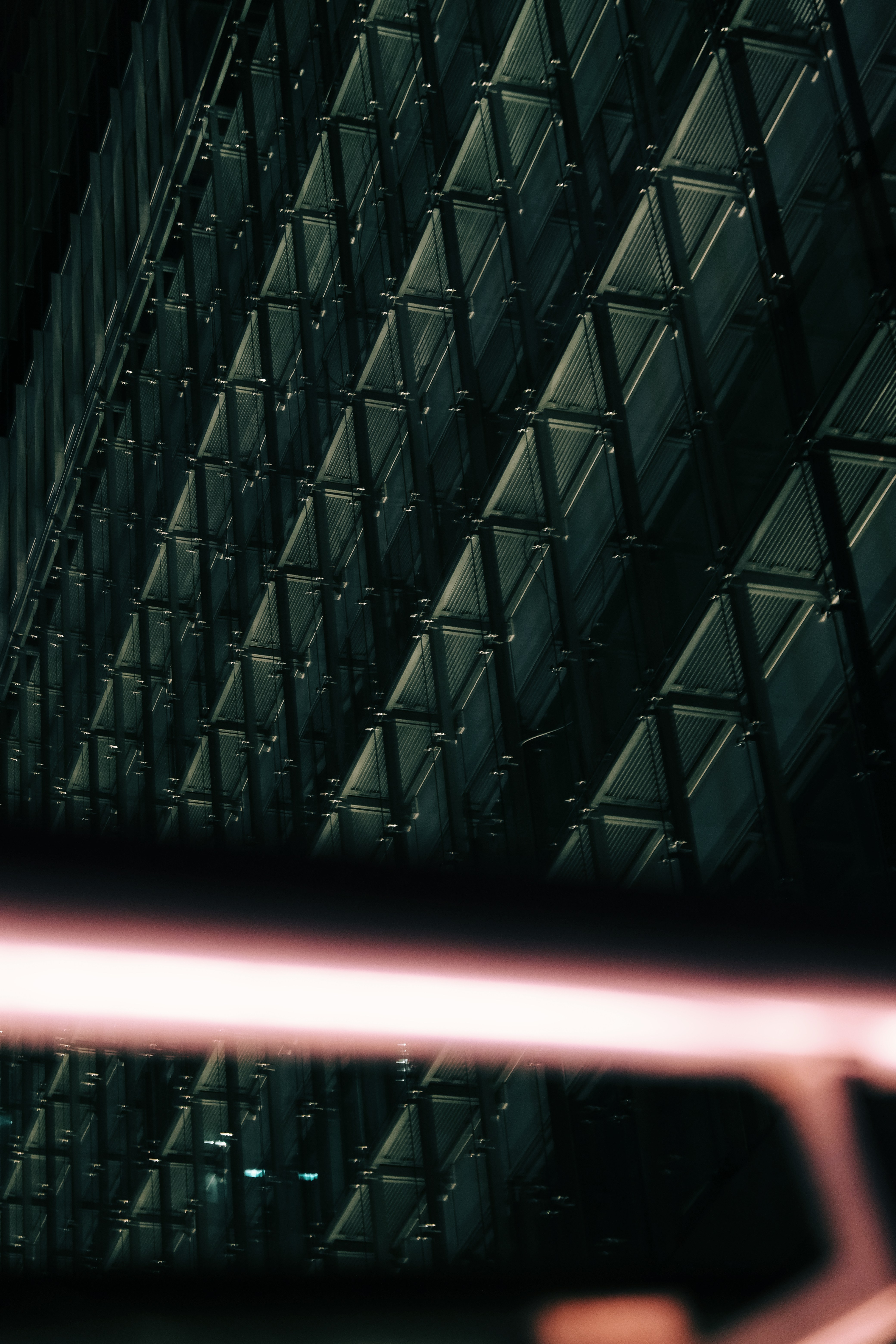 Neon Ribbon Across a Faceted Glass Facade