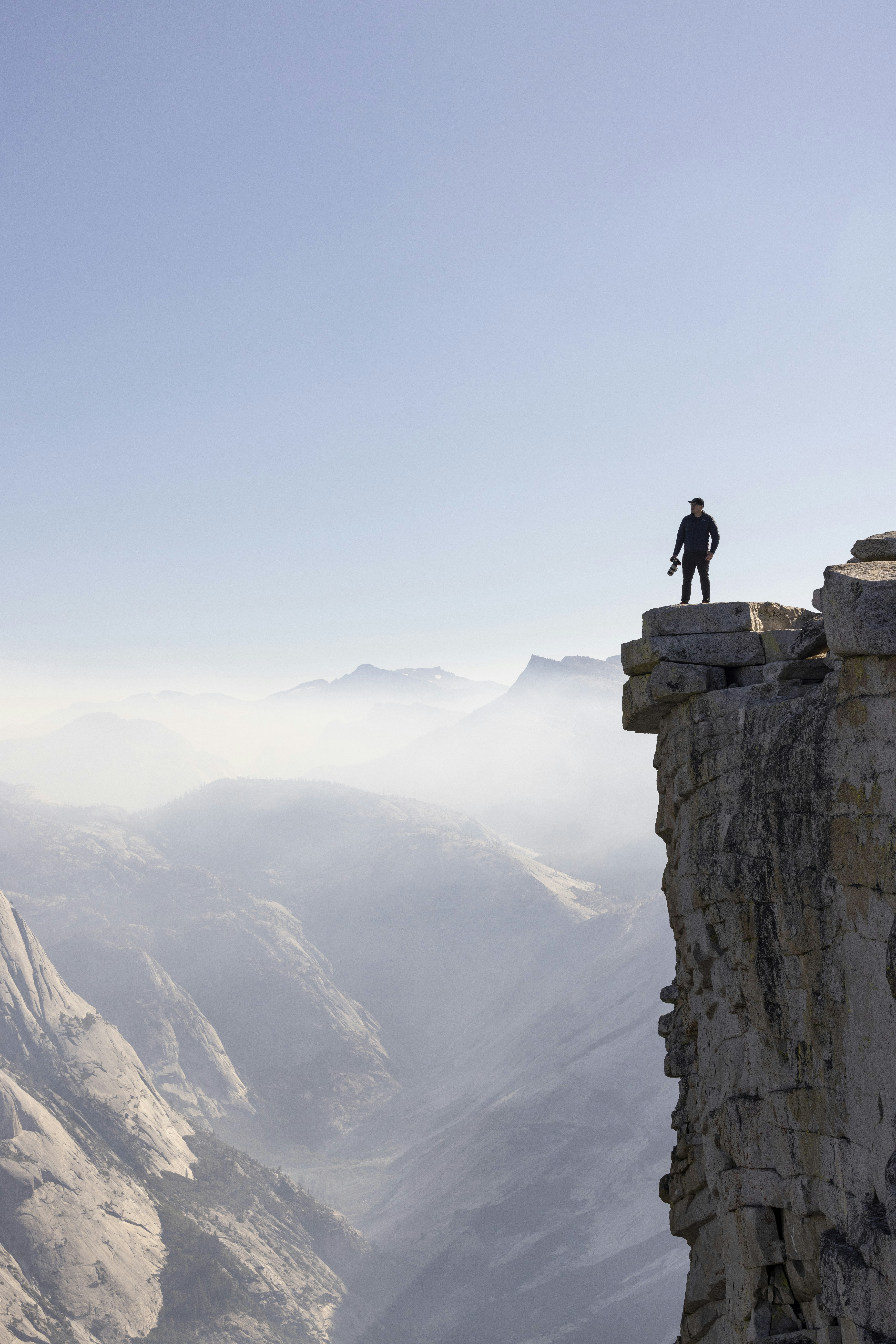 A person standing on a ledge overlooking a valley with snow photo ...