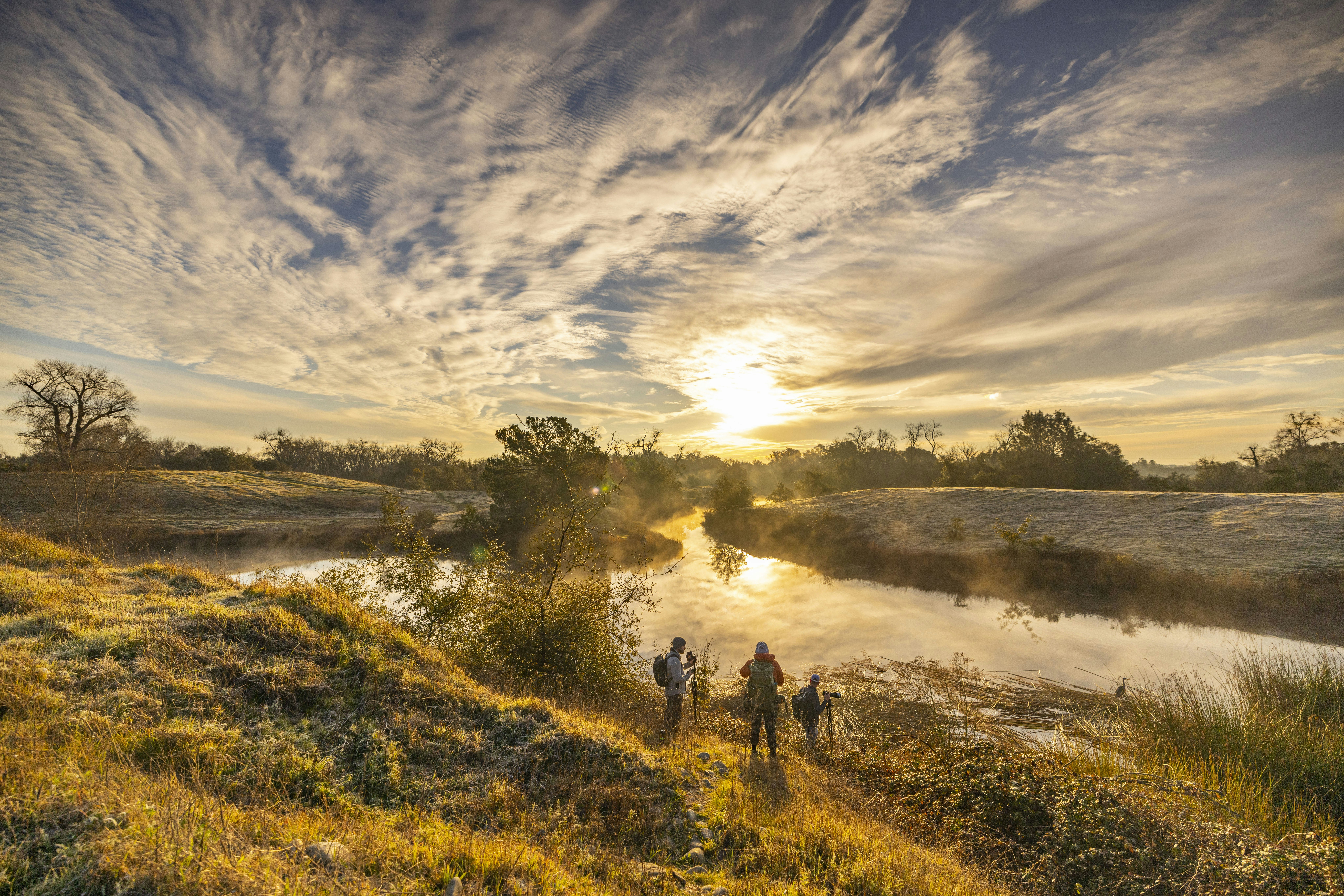 A group of people walking on a trail by a river photo – Free Land Image ...