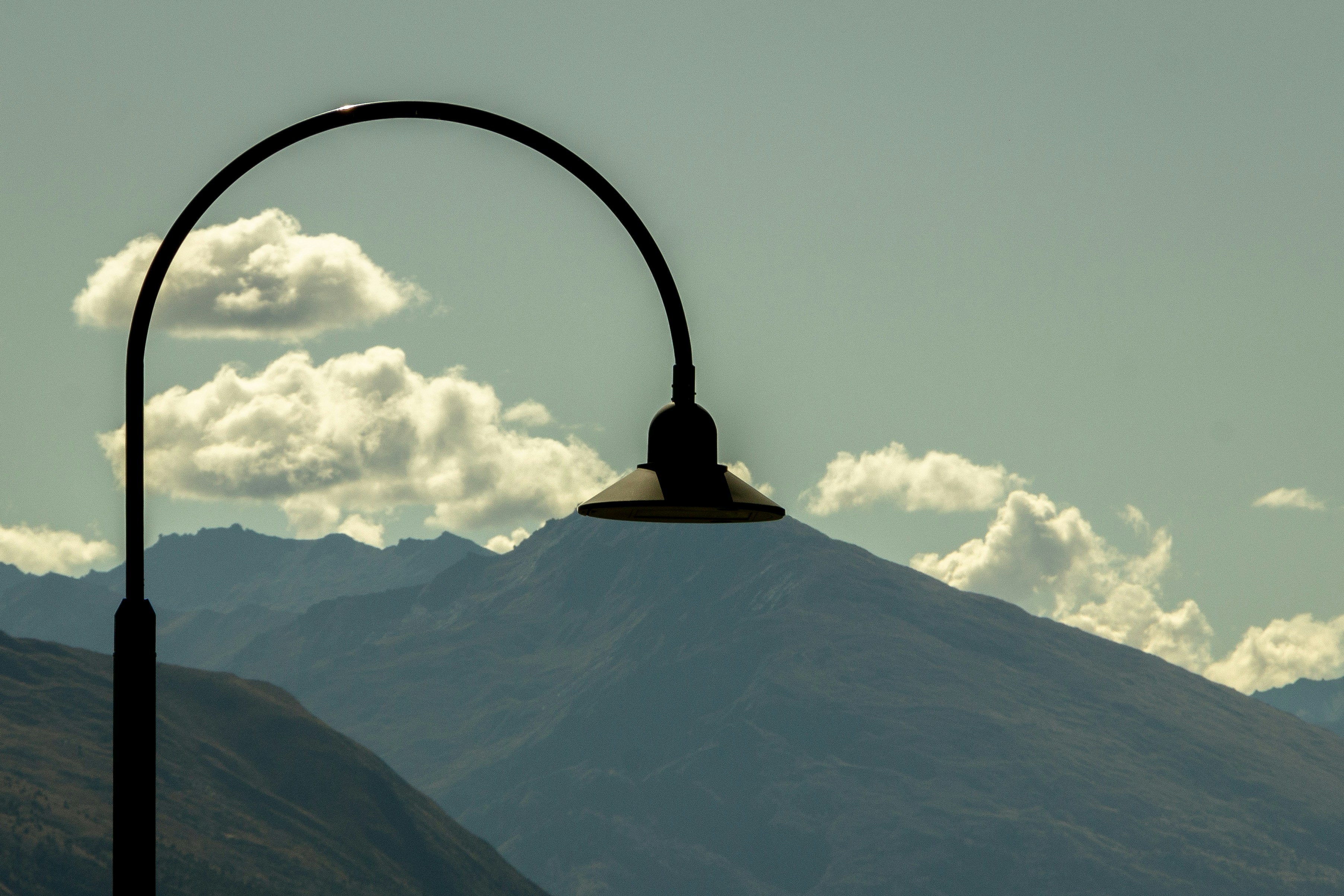 Arc on the ridge: a solitary lamp framing alpine silhouettes at dusk