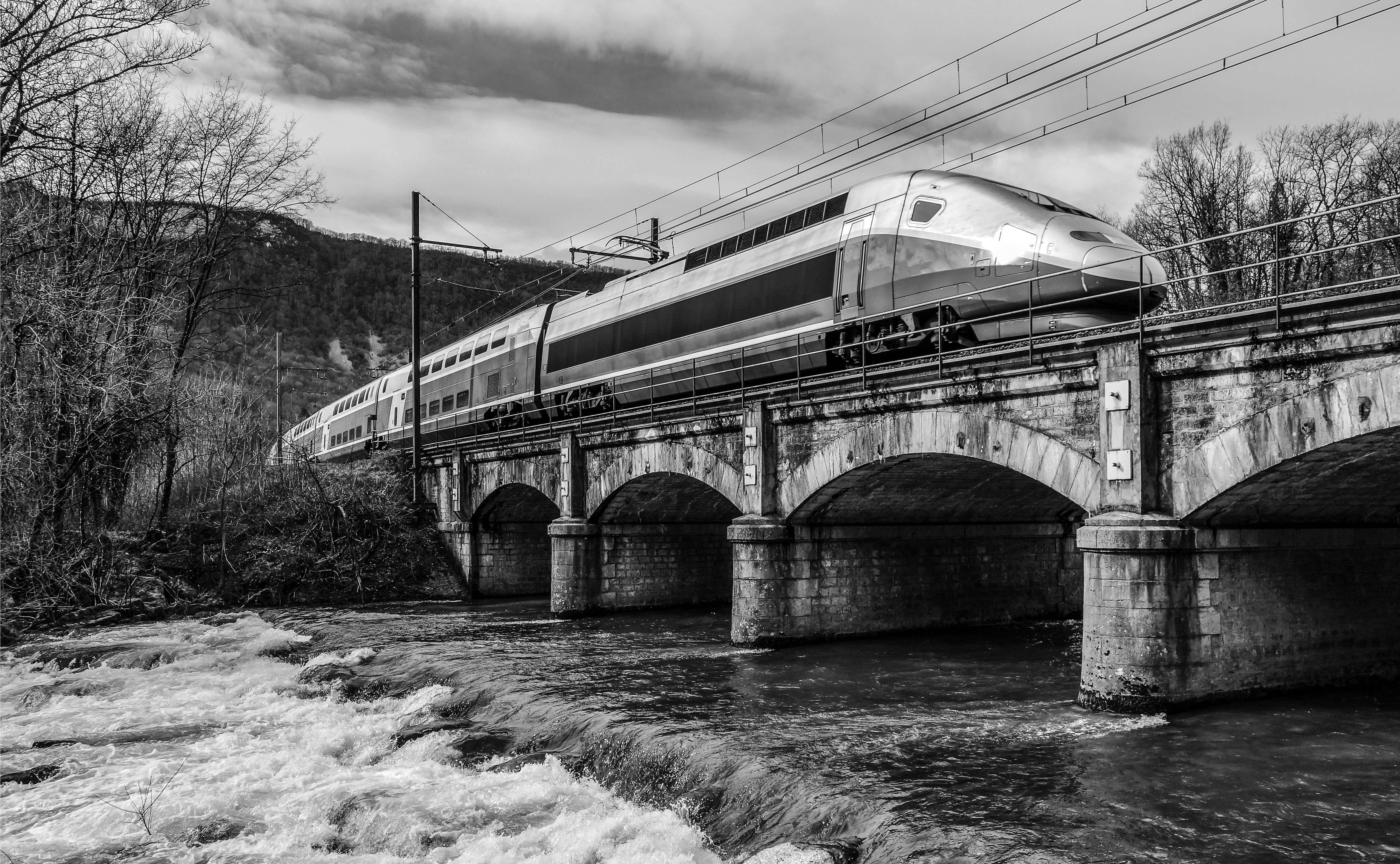 Monochrome Rails Across Time: Train Crossing a Weathered Stone Bridge