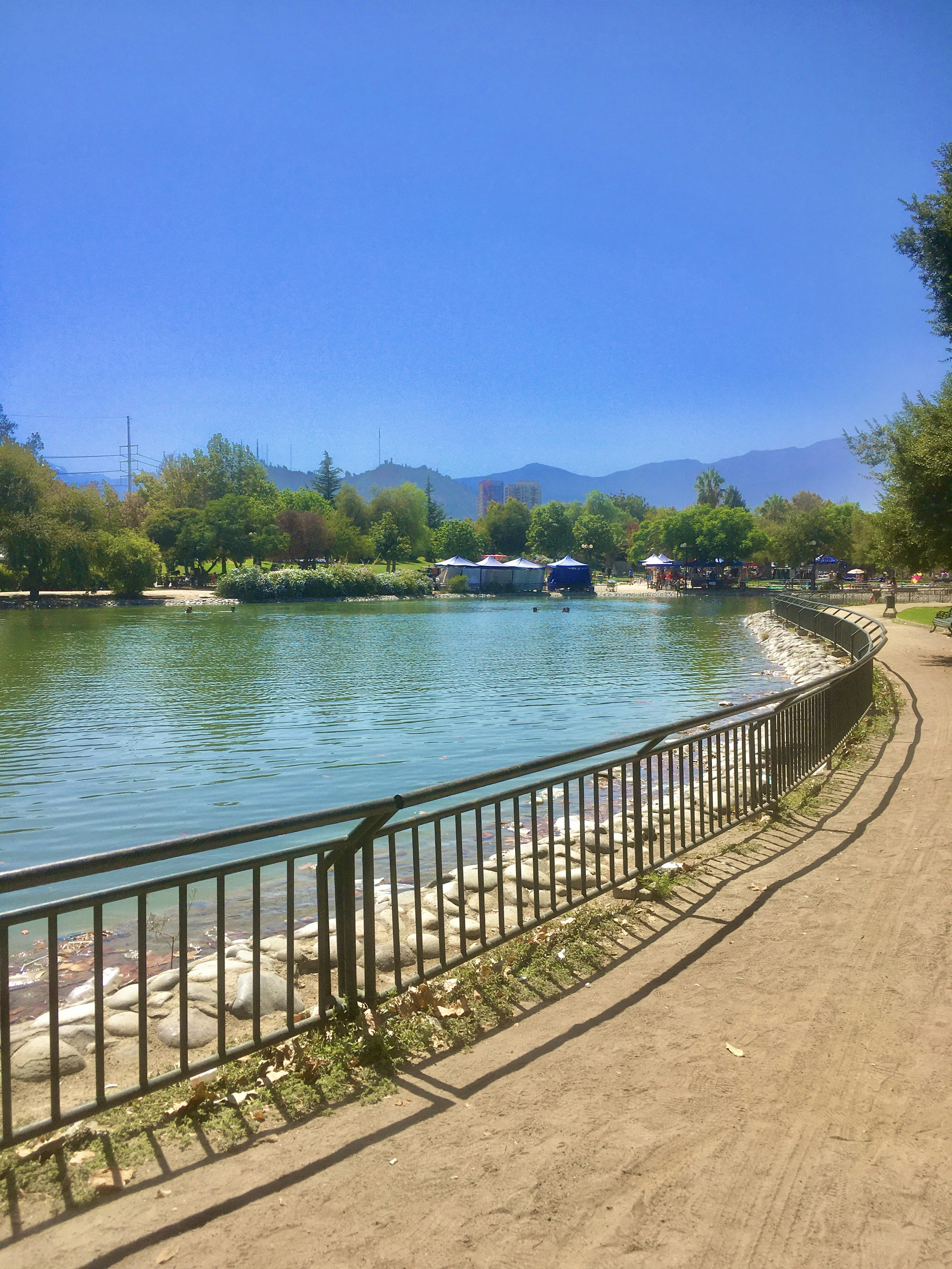 Lakeside Promenade: Curved Rails, Quiet Water, and Tents in the Park