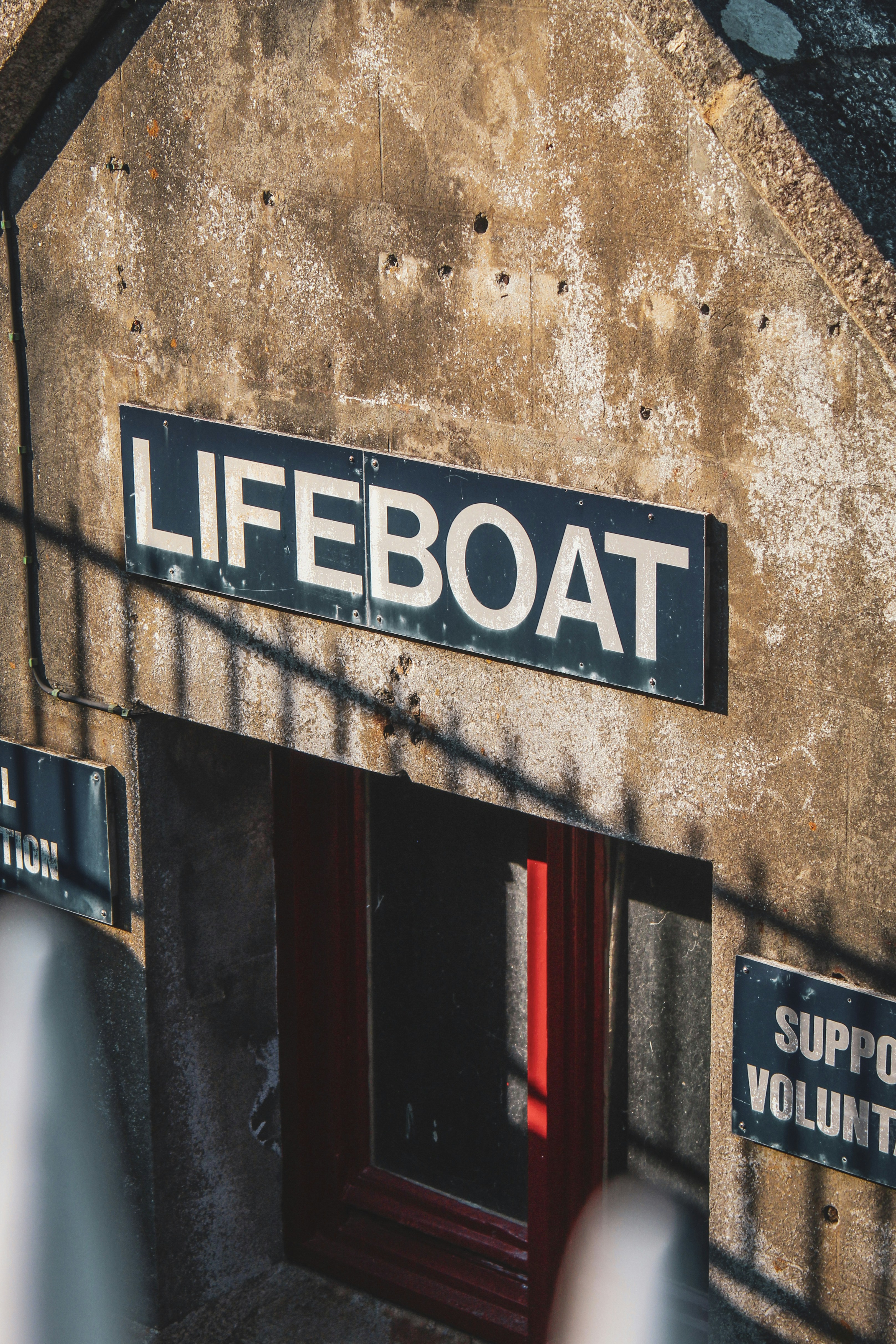 Weathered Lifeboat House: Sunlit Sign and Red Door