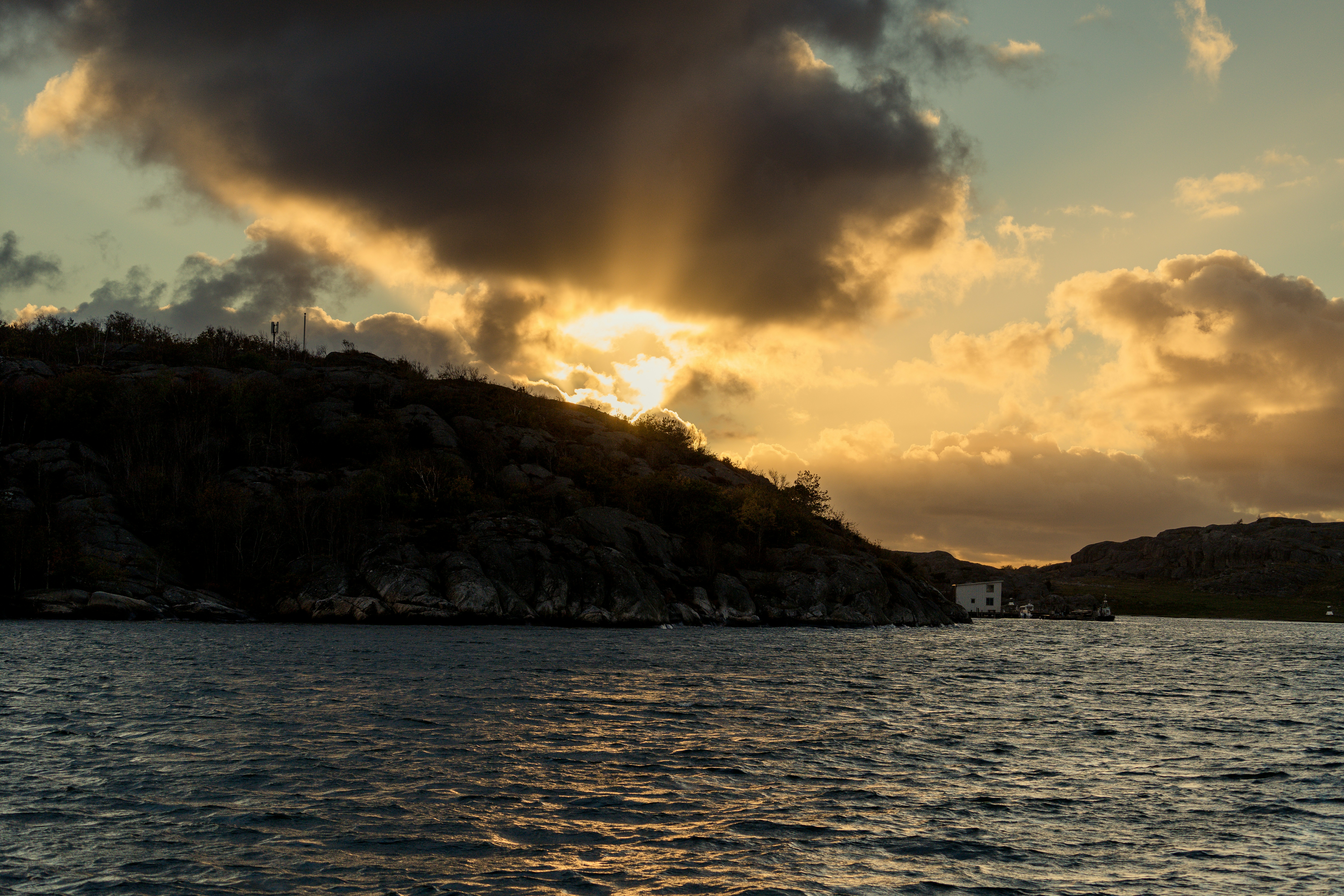 a body of water with a rocky cliff and a building on the side